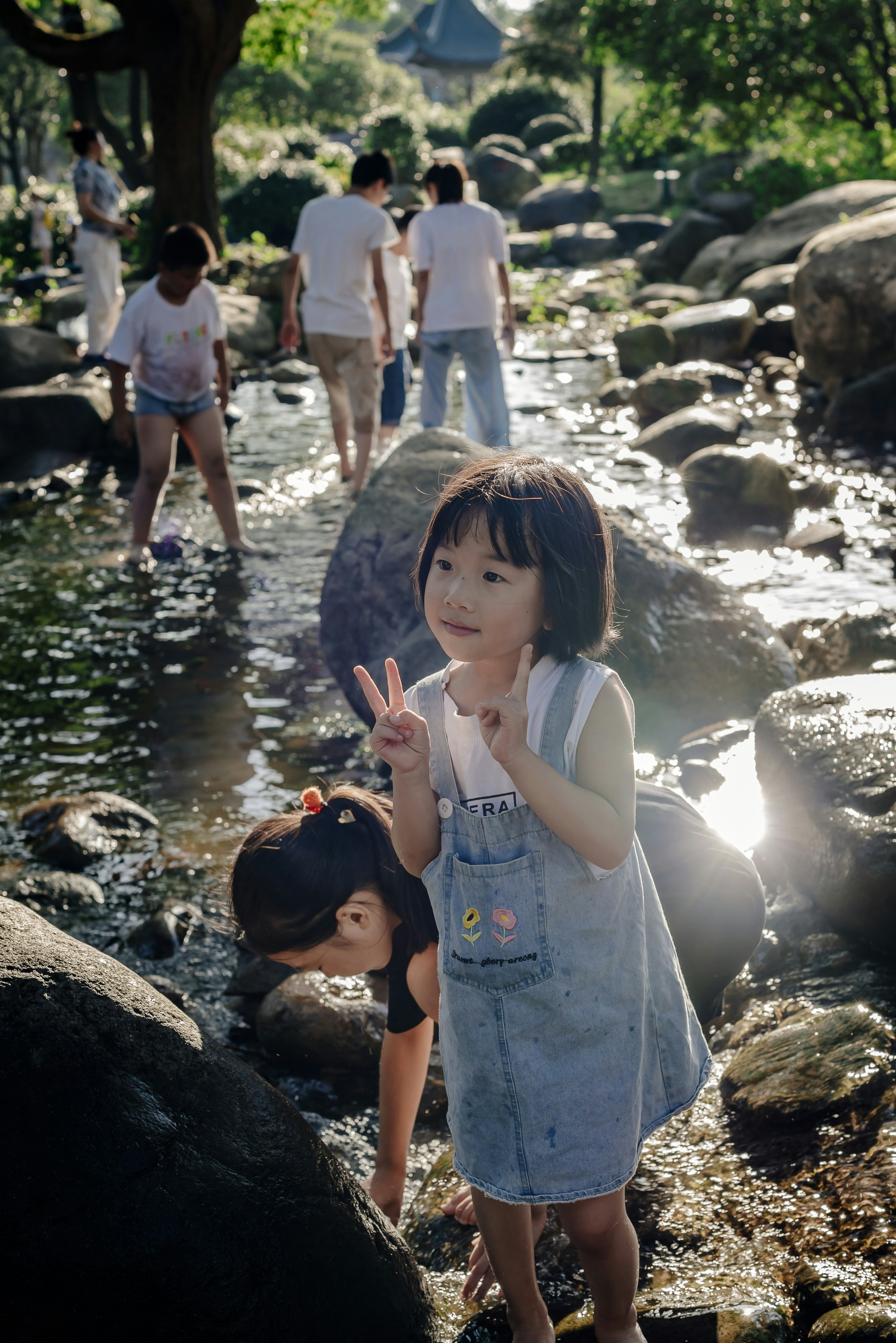A little girl standing next to a river giving the peace sign photo ...