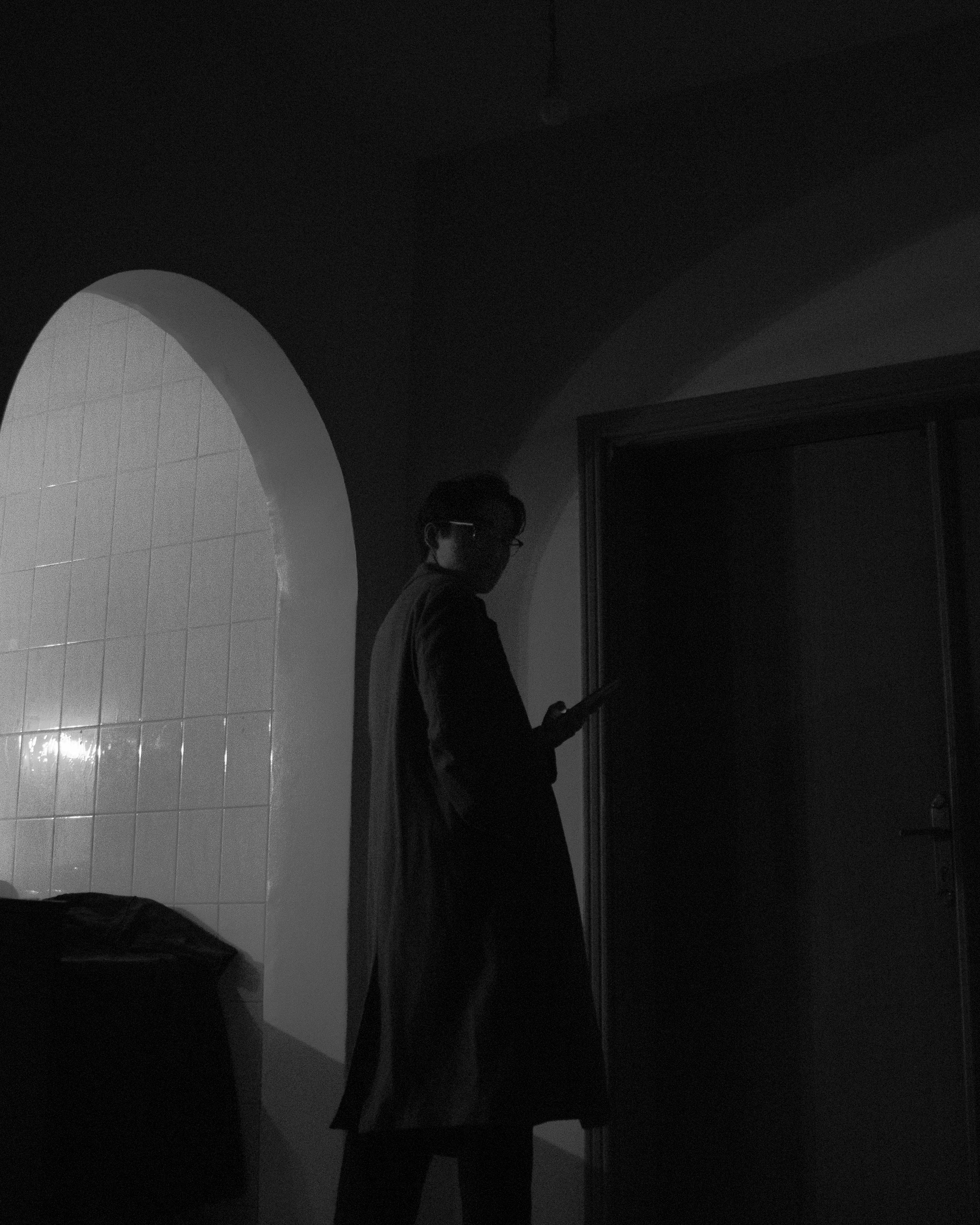 Oculus at Dusk: A Lone Figure in a Tiled Archway Corridor
