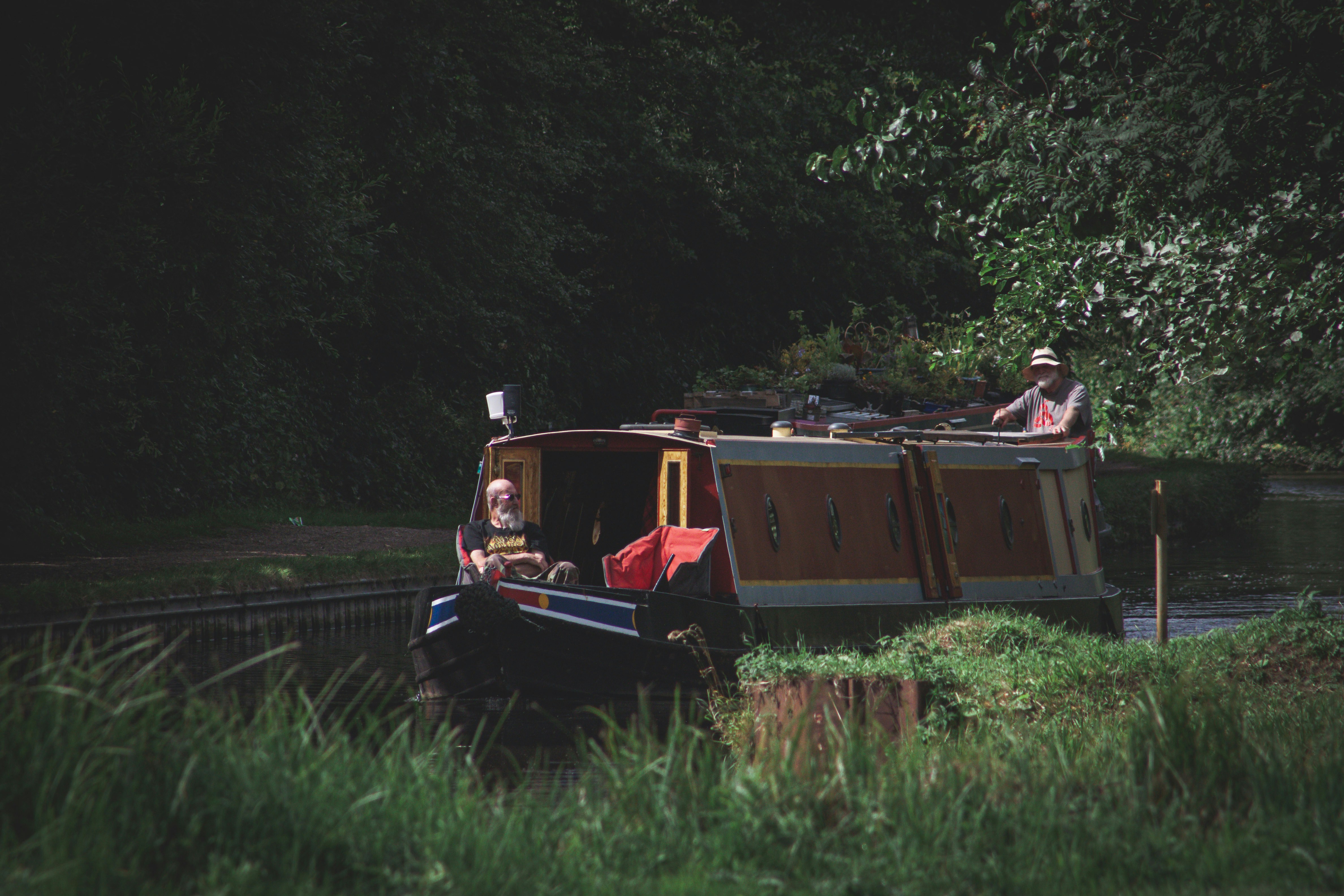 Narrowboat gliding along a lush, tree-lined canal under soft evening light.