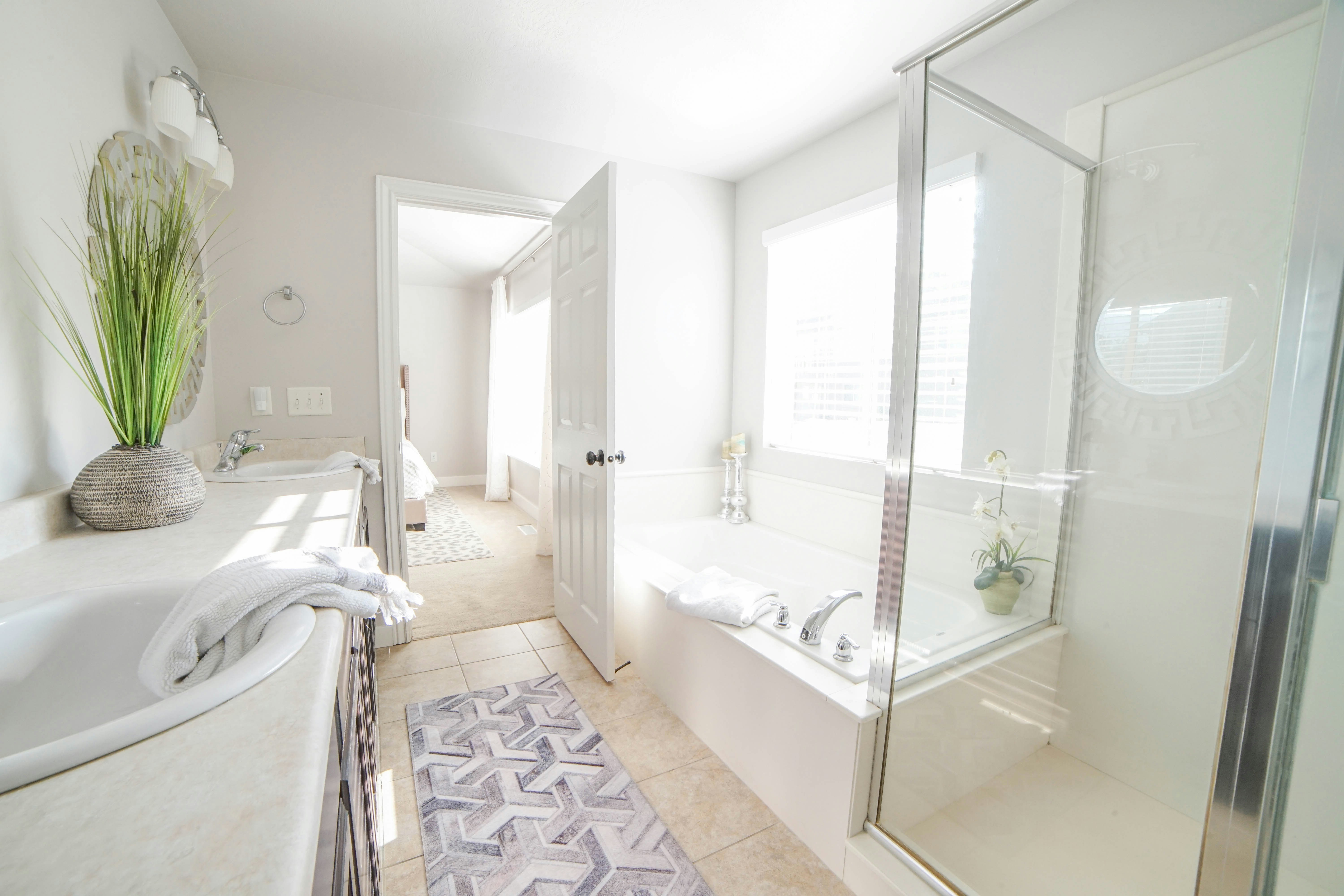 Bright and airy bathroom featuring a soaking tub, glass shower, and elegant decor. Natural light floods the space, enhancing its tranquil atmosphere.