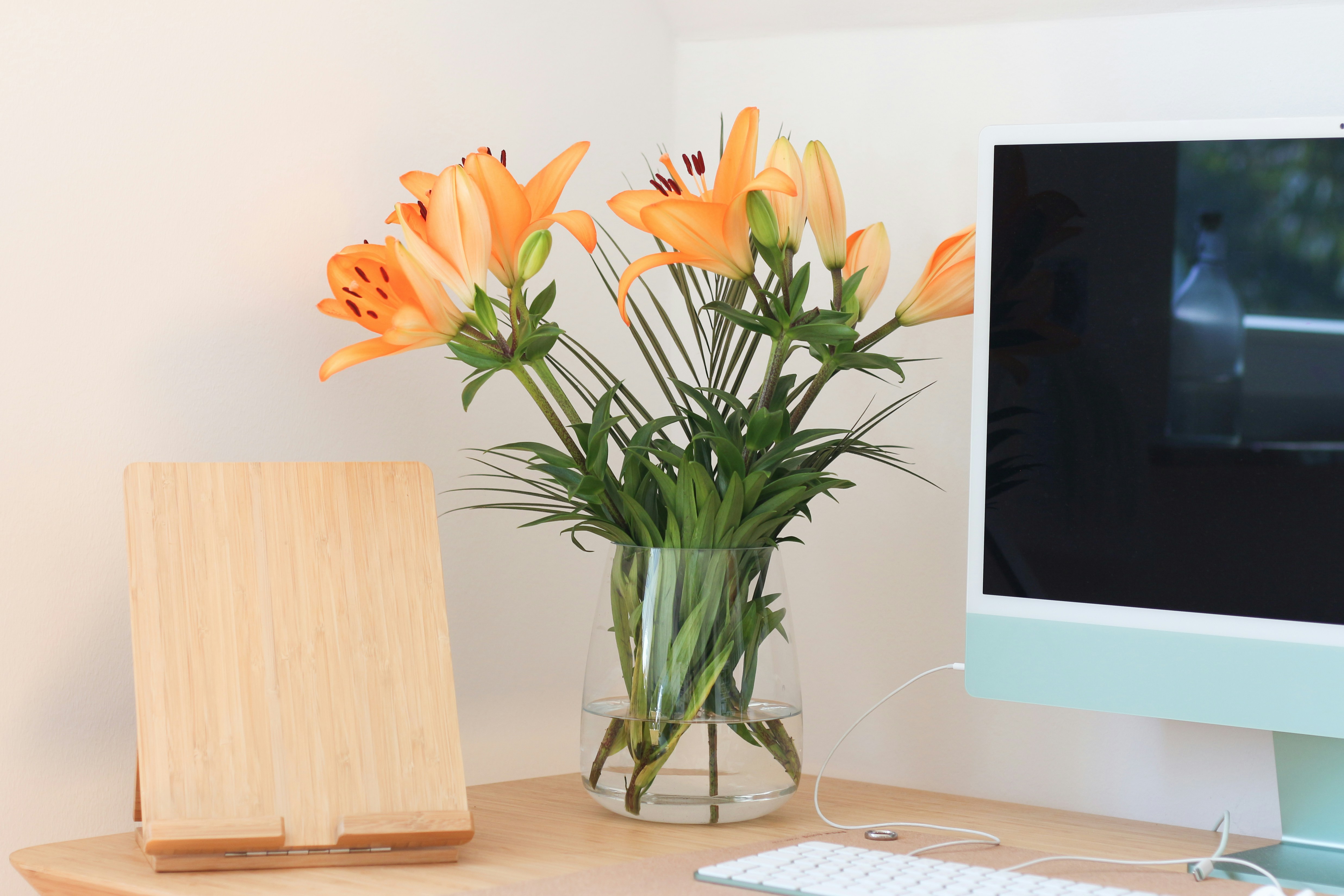 Sunlit Desk Bouquet: Orange Lilies by a Glass Vase and a Modern Monitor