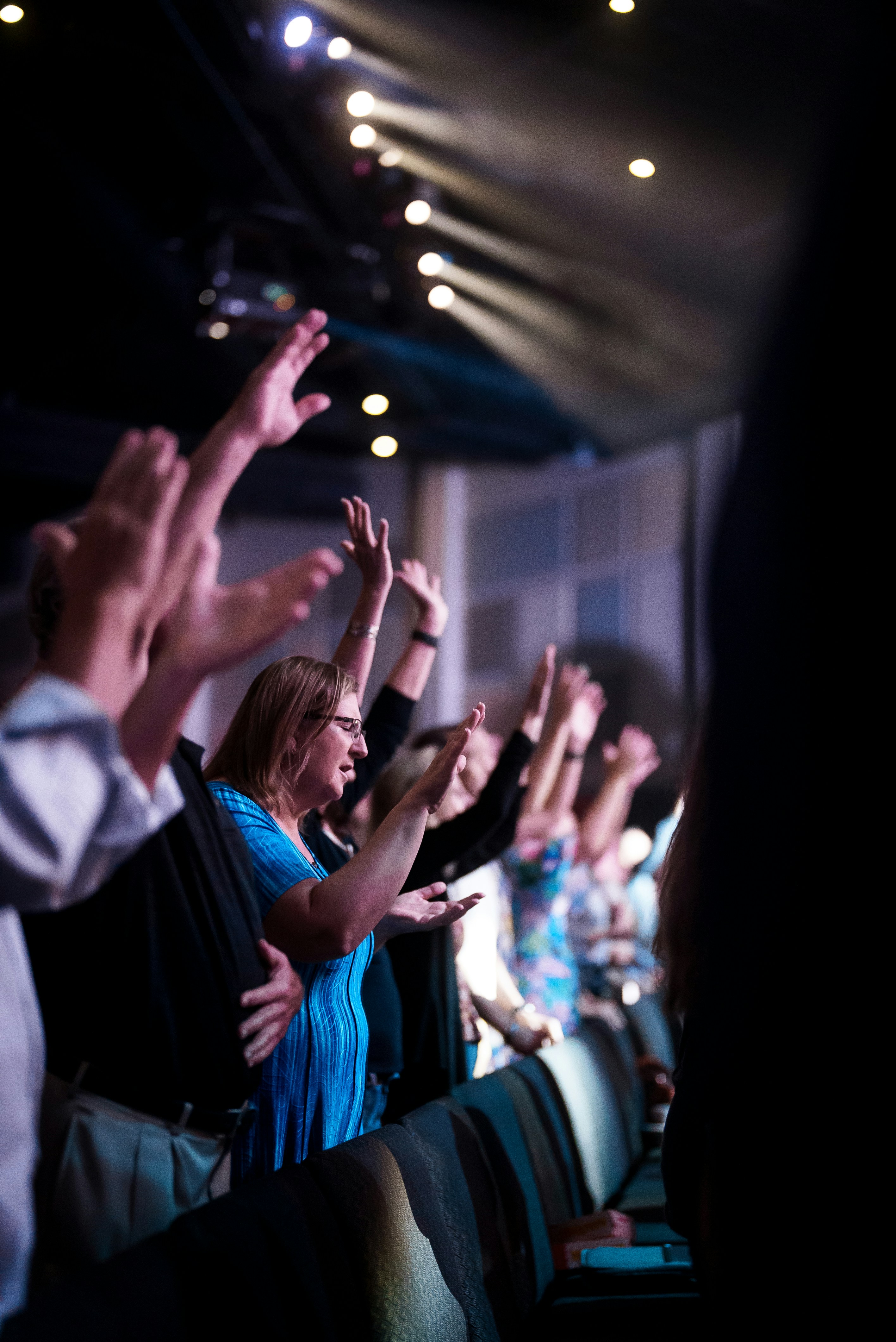Audience members enthusiastically raising their hands during a performance in a theater setting.