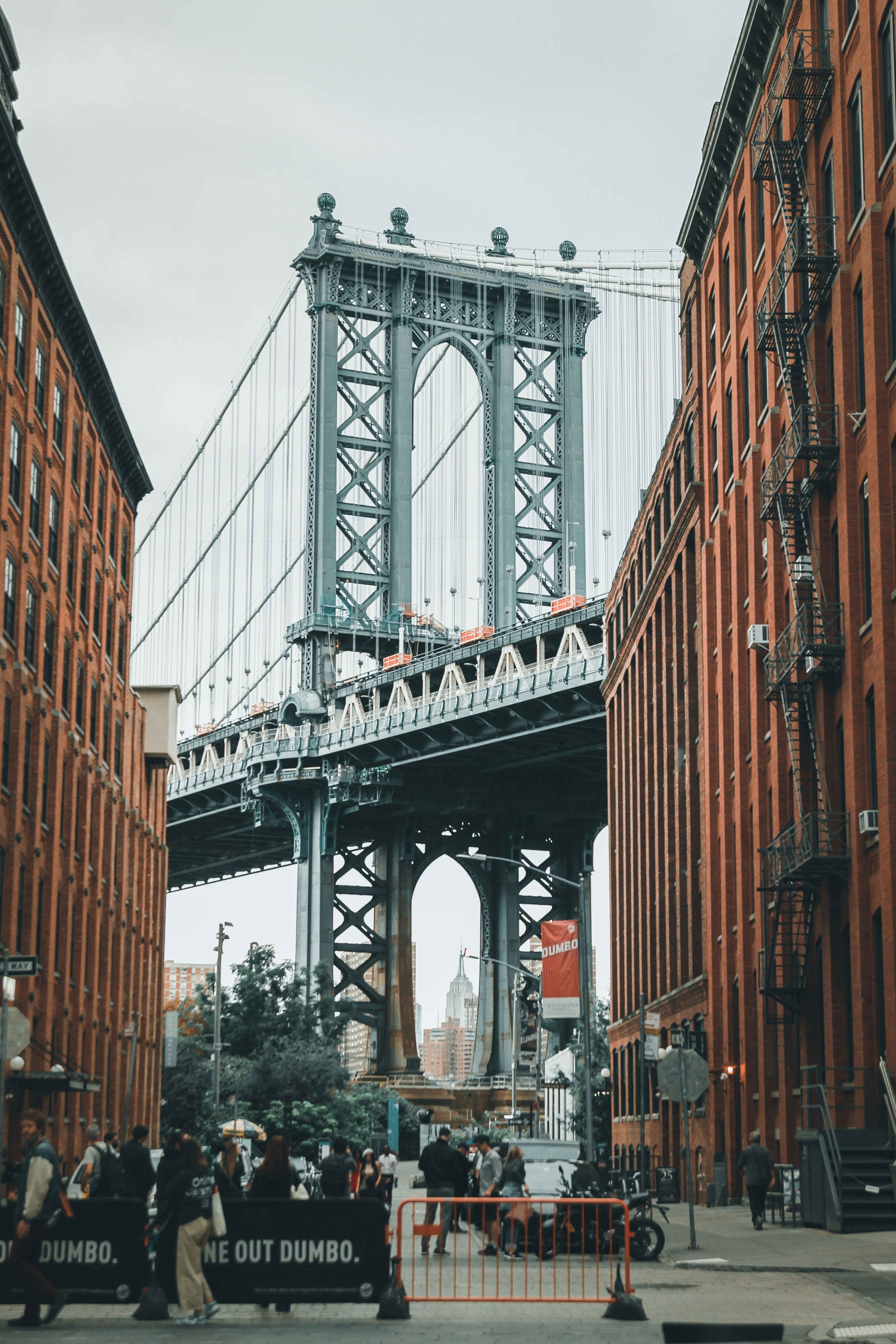 Iconic Manhattan Bridge framed by historic brick buildings in DUMBO, Brooklyn, showcasing urban life and architecture.