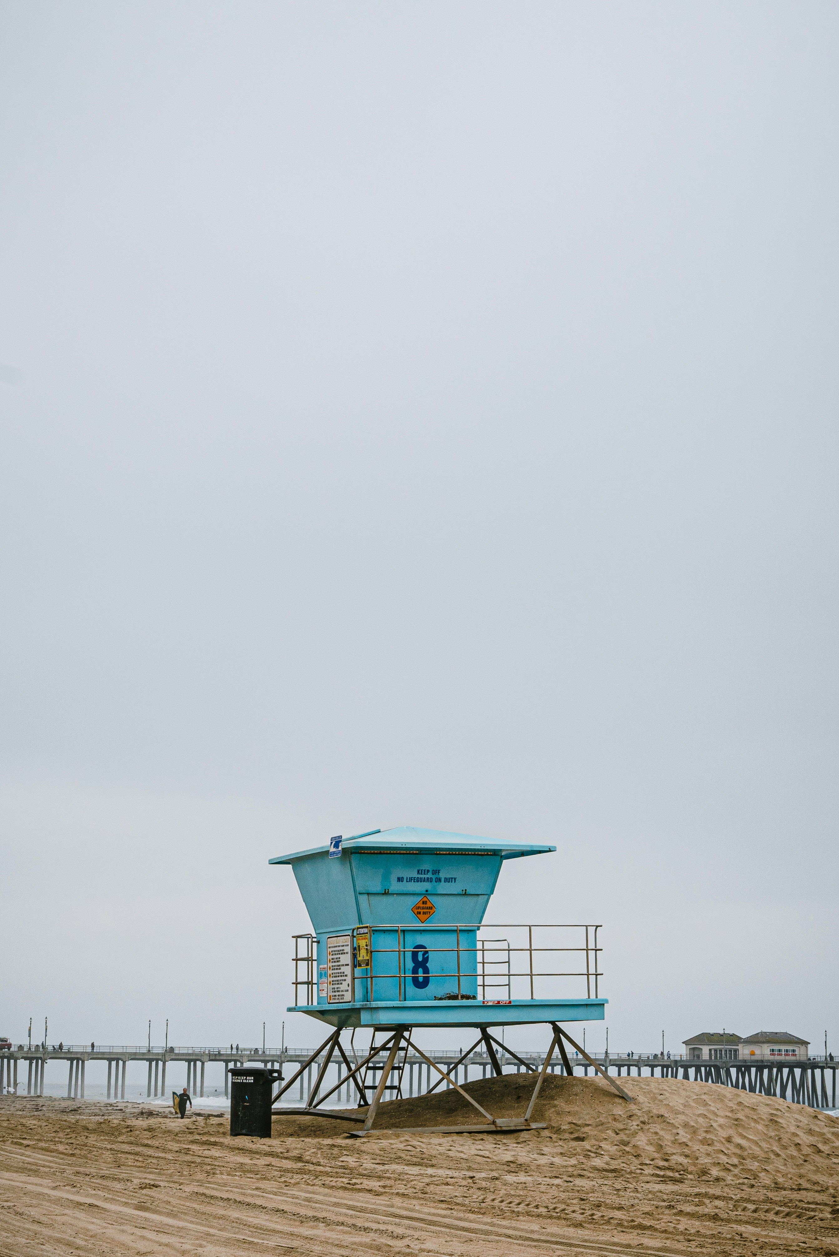 Vibrant blue lifeguard tower overlooking a sandy beach under a cloudy sky. The structure stands as a guardian of safety along the shore.