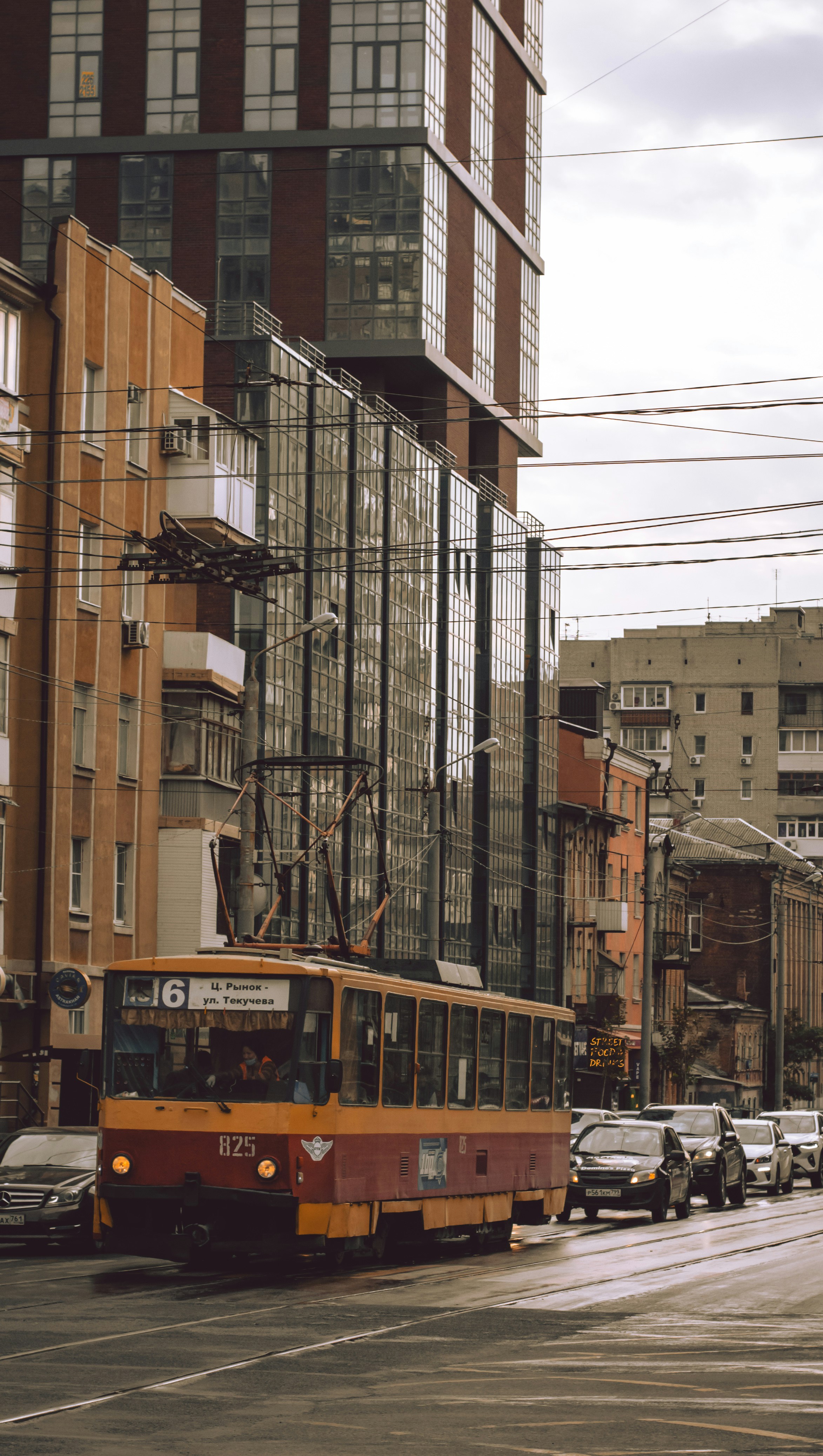 Orange Tram Threading a Rainy City Between Glass Towers and Wires