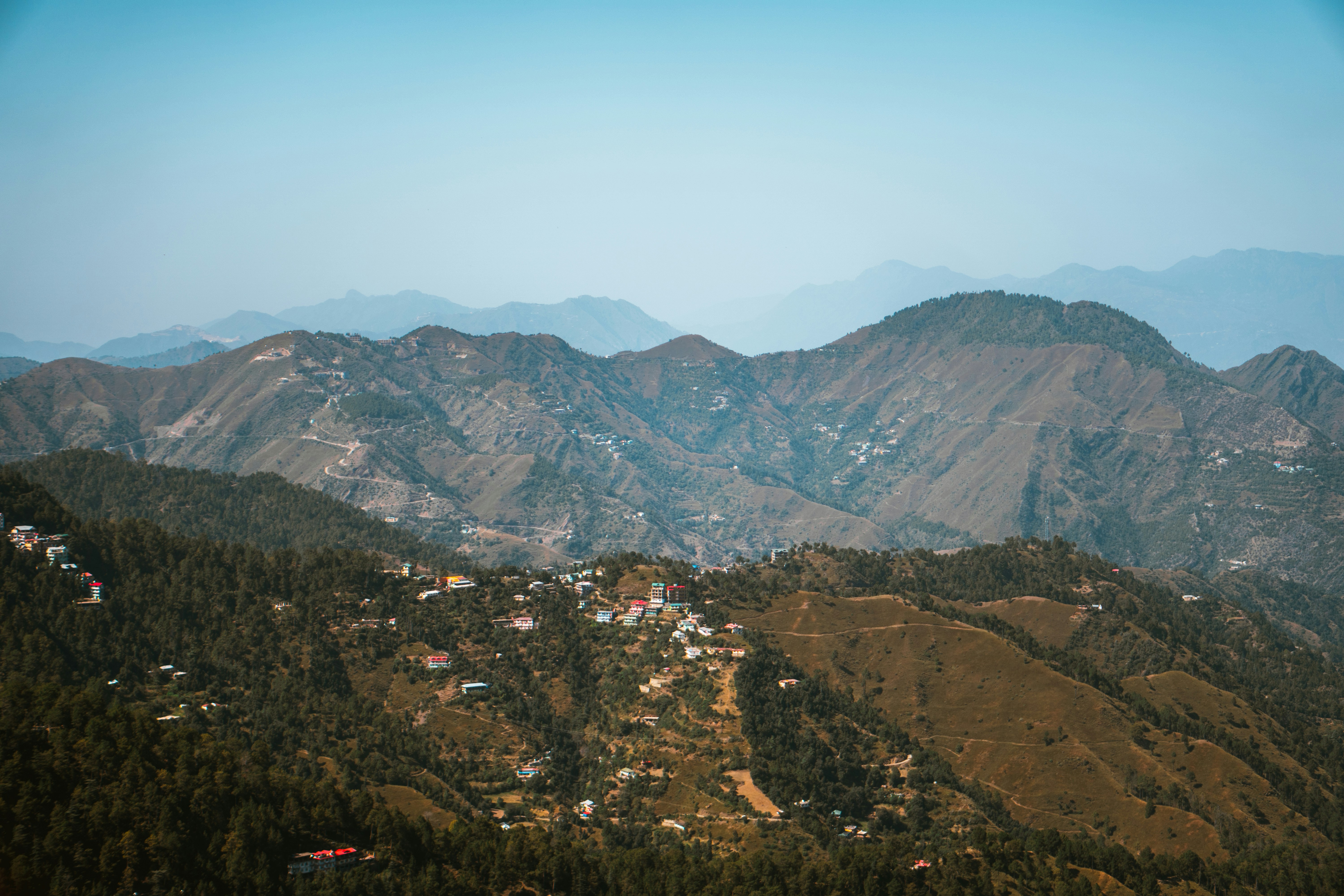 Expansive view of a mountainous landscape dotted with small settlements, showcasing the harmony between nature and human habitation.