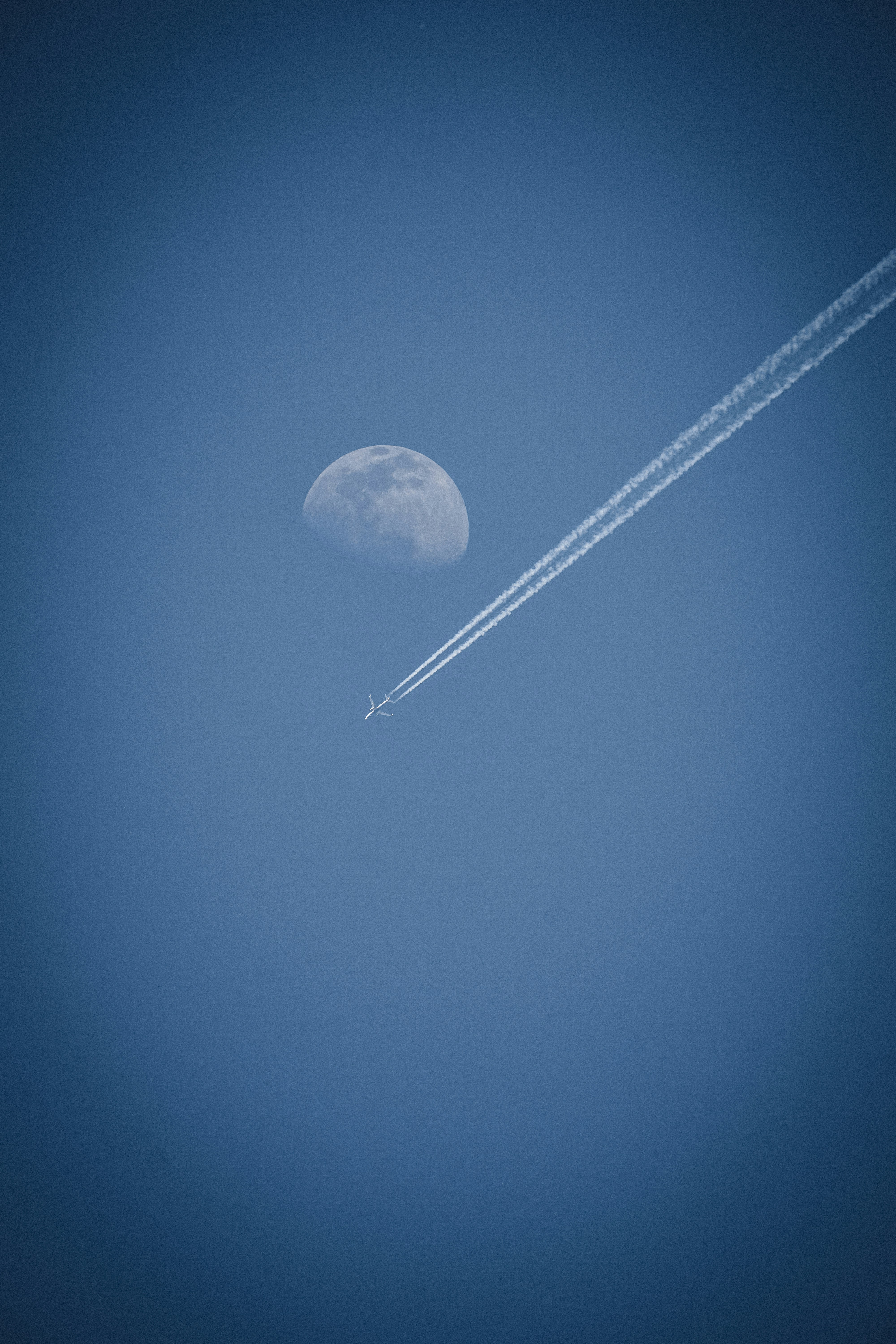Moon and Jet Trail Across a Cerulean Sky