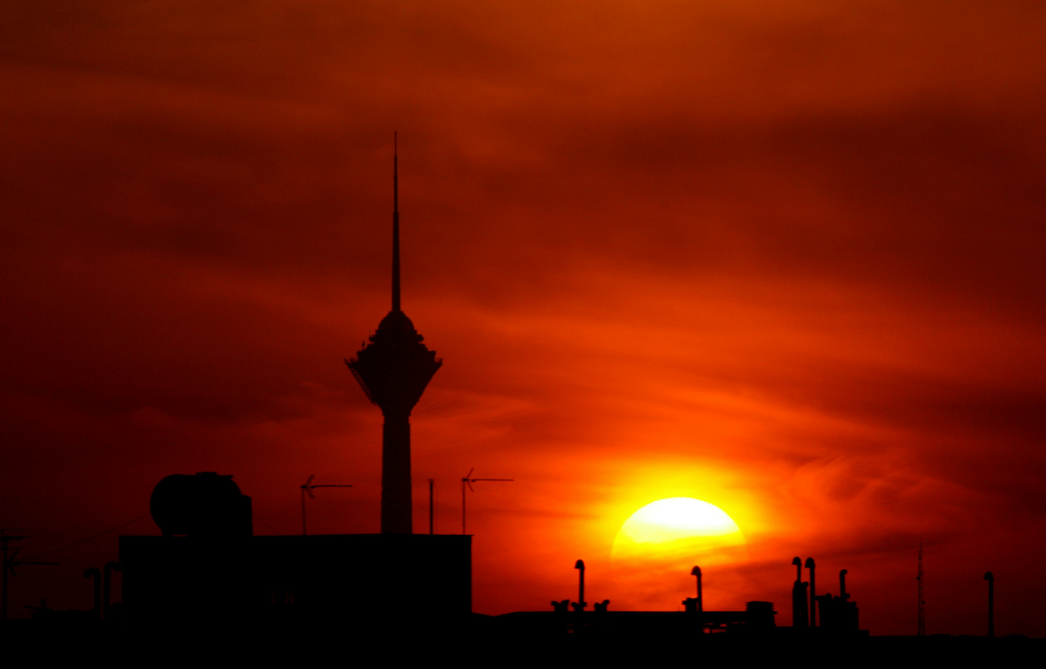 The sun is setting behind a tall tower photo – Free Nature Image on ...