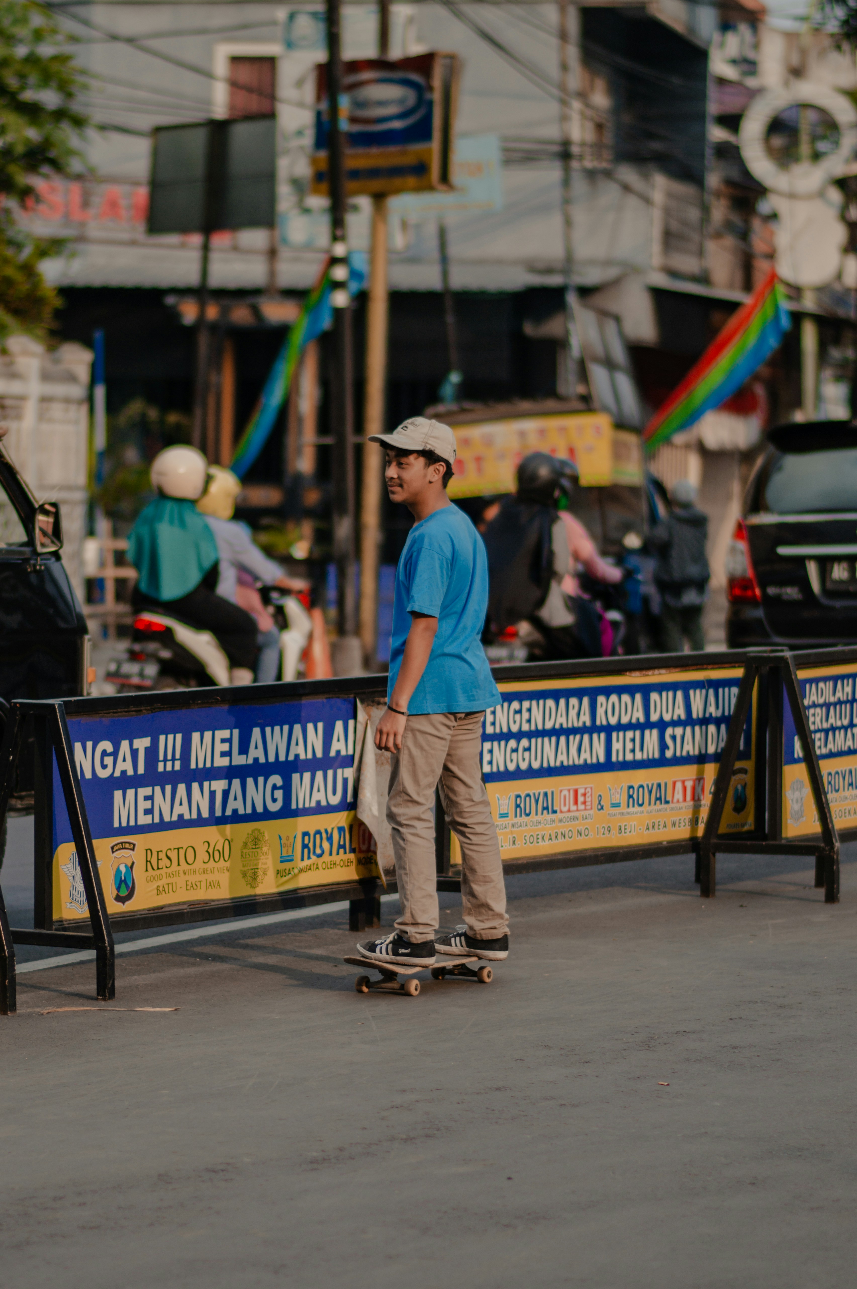 Blue Tee Skater Pauses at the Barricade: A Quiet Moment in a Busy Street