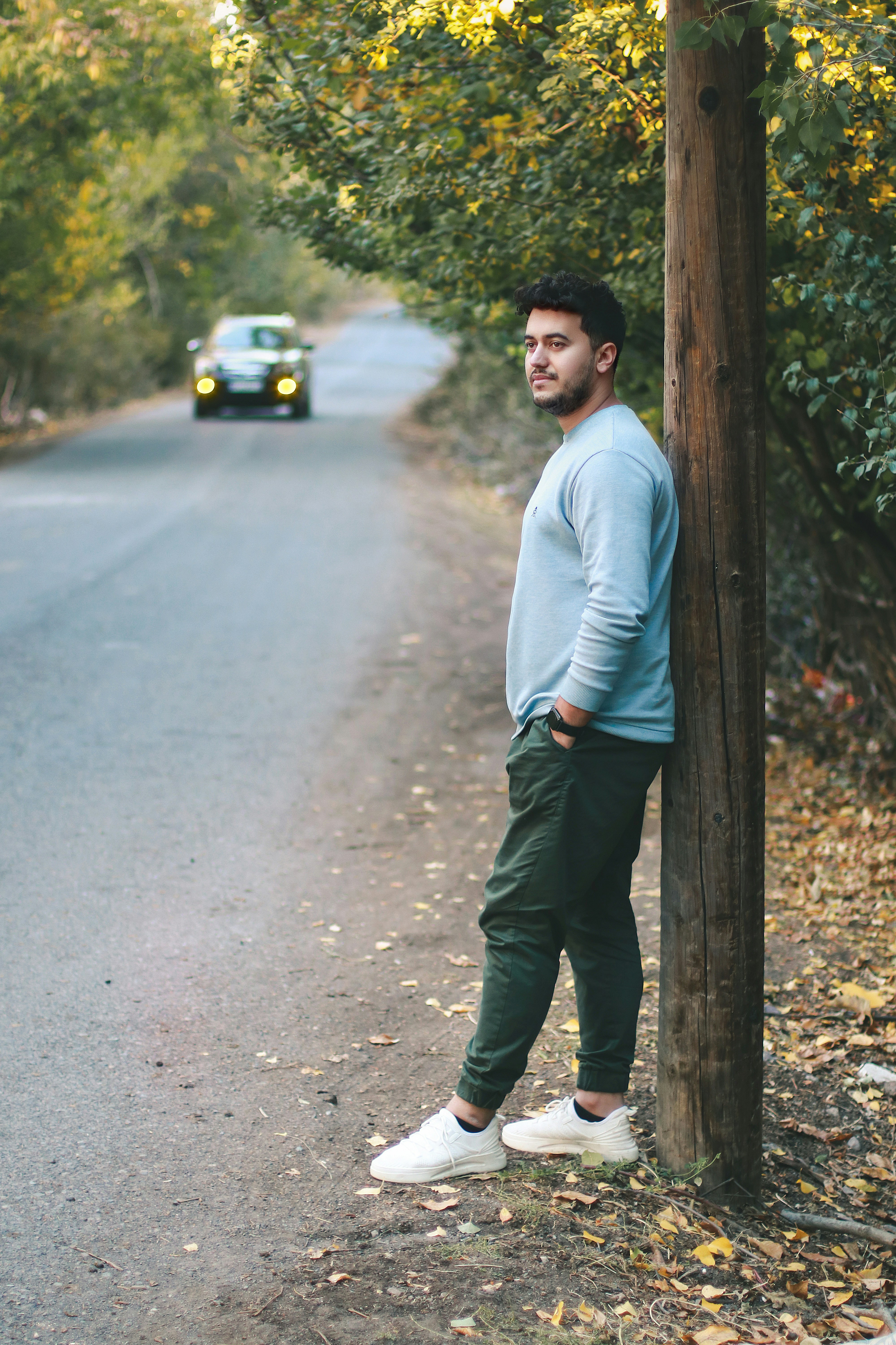 A man leaning against a pole on the side of a road photo – Free ...