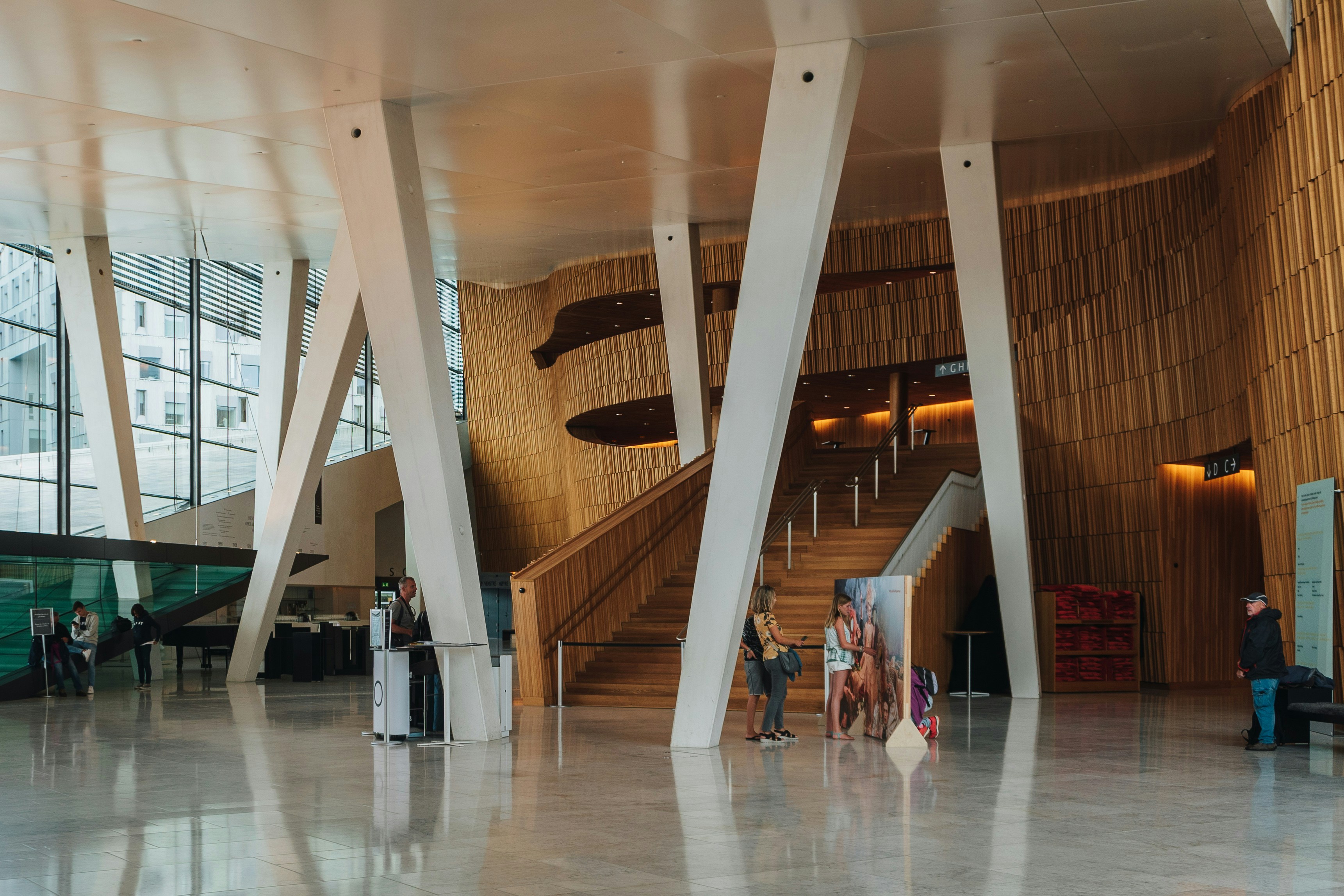 Interior of a contemporary building showcasing wooden accents and striking architectural lines. A staircase leads to an upper level, enhancing the spatial dynamics.