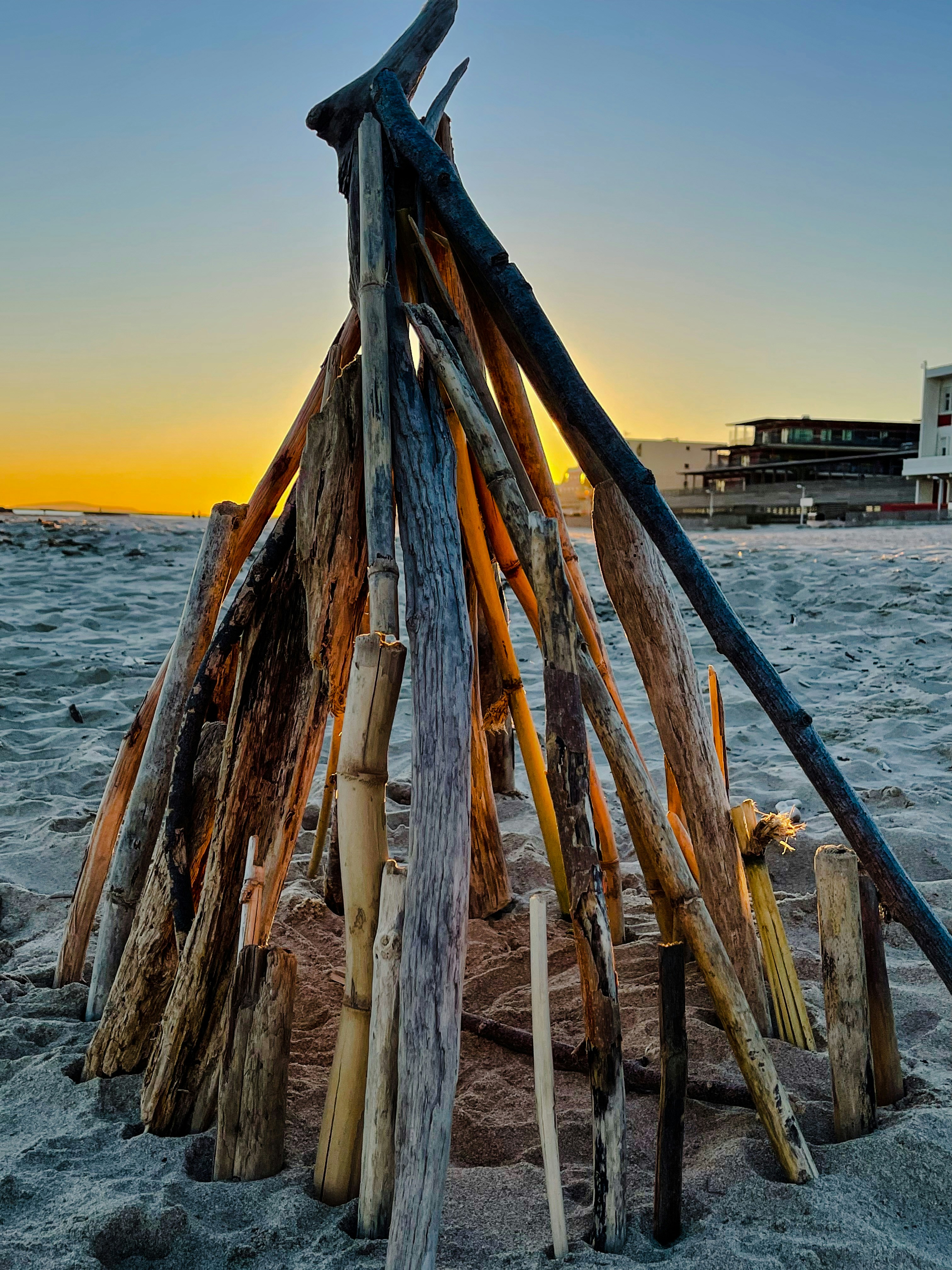 A pile of sticks sitting on top of a sandy beach photo – Free Water ...