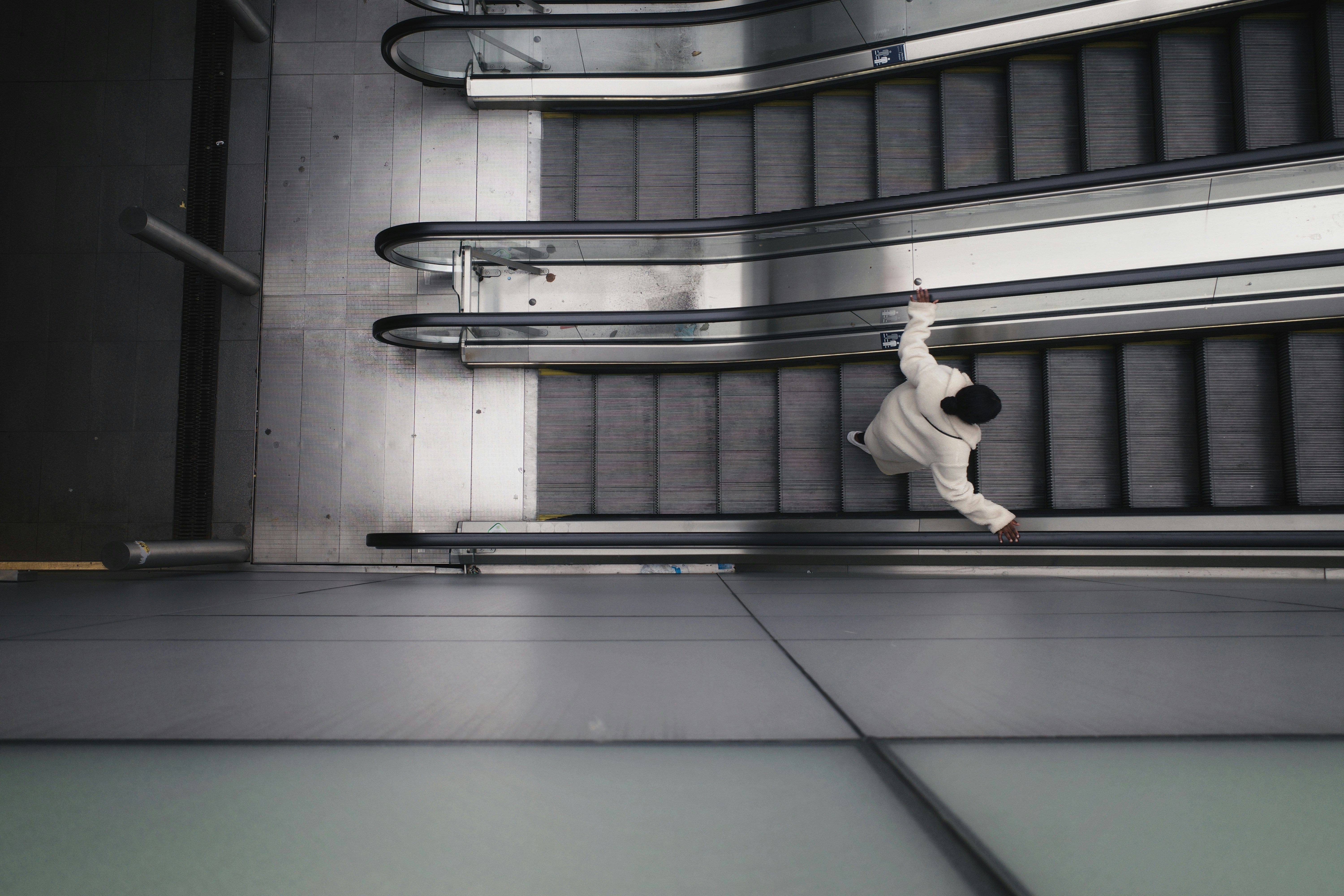 A lone figure traverses a sleek escalator in a contemporary setting, highlighting the interplay of movement and design.