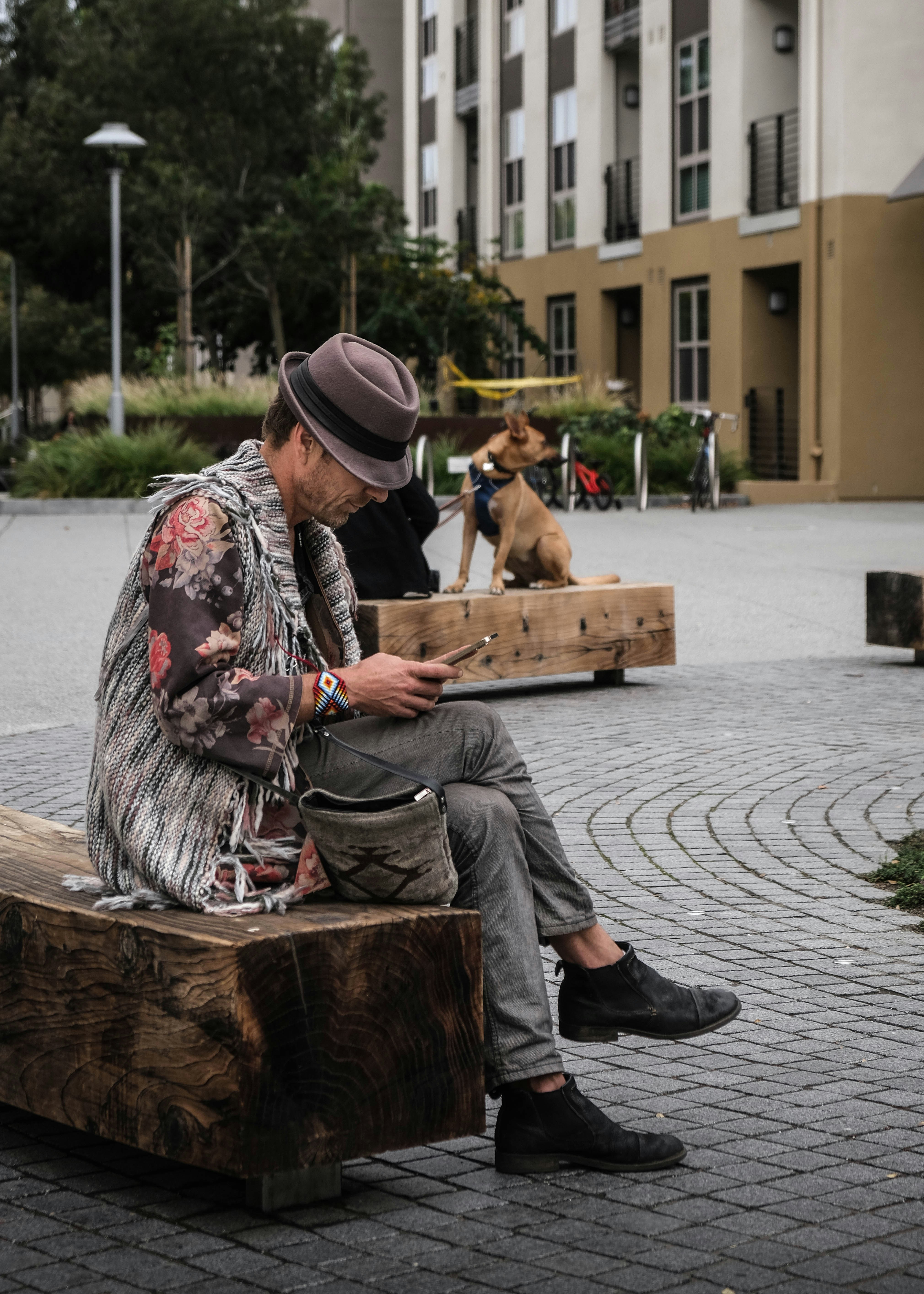 Benchbound Moment in an Urban Square: A Floral-Scarved Man and a Watchful Dog