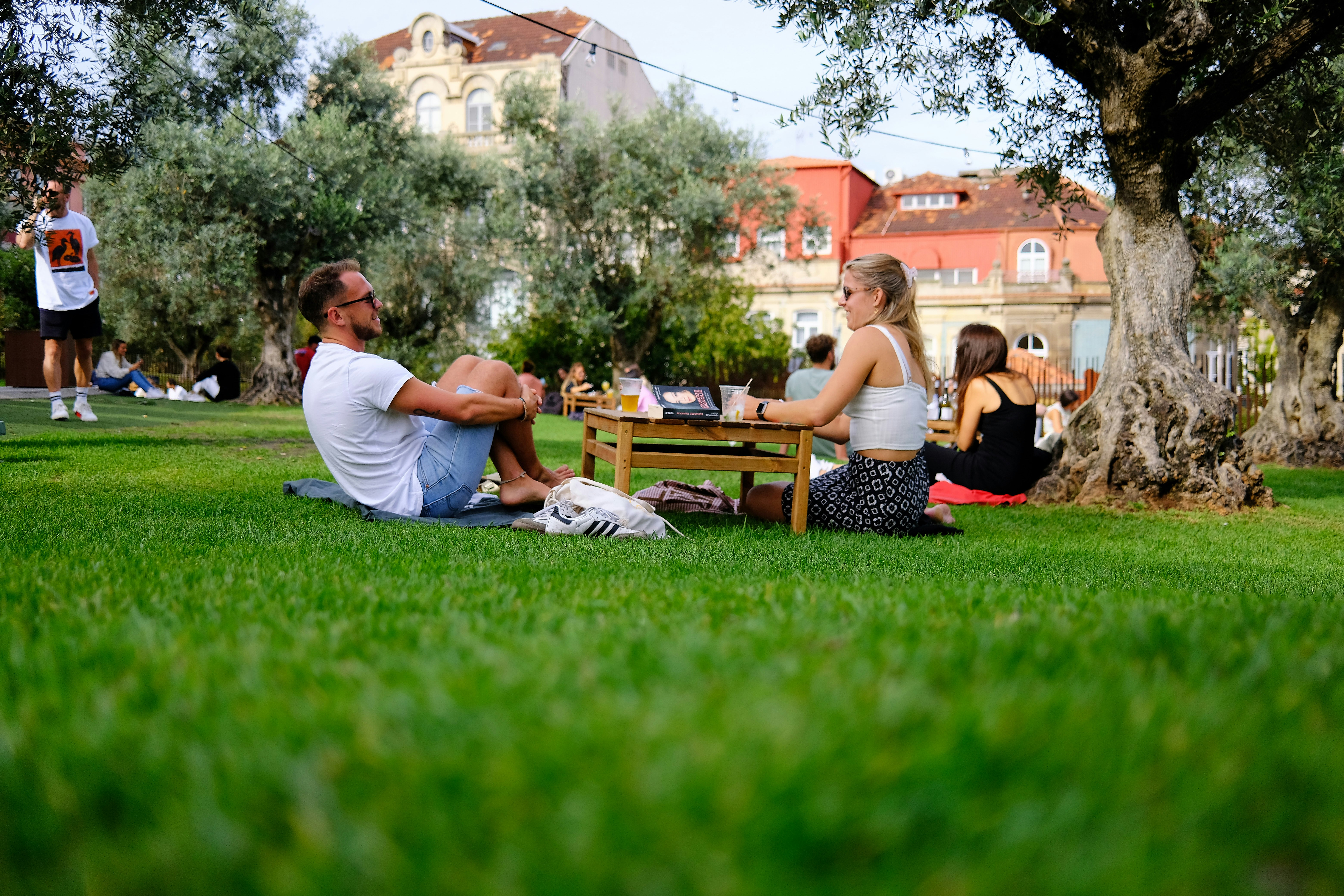 a man and a woman sitting on the grass in a park