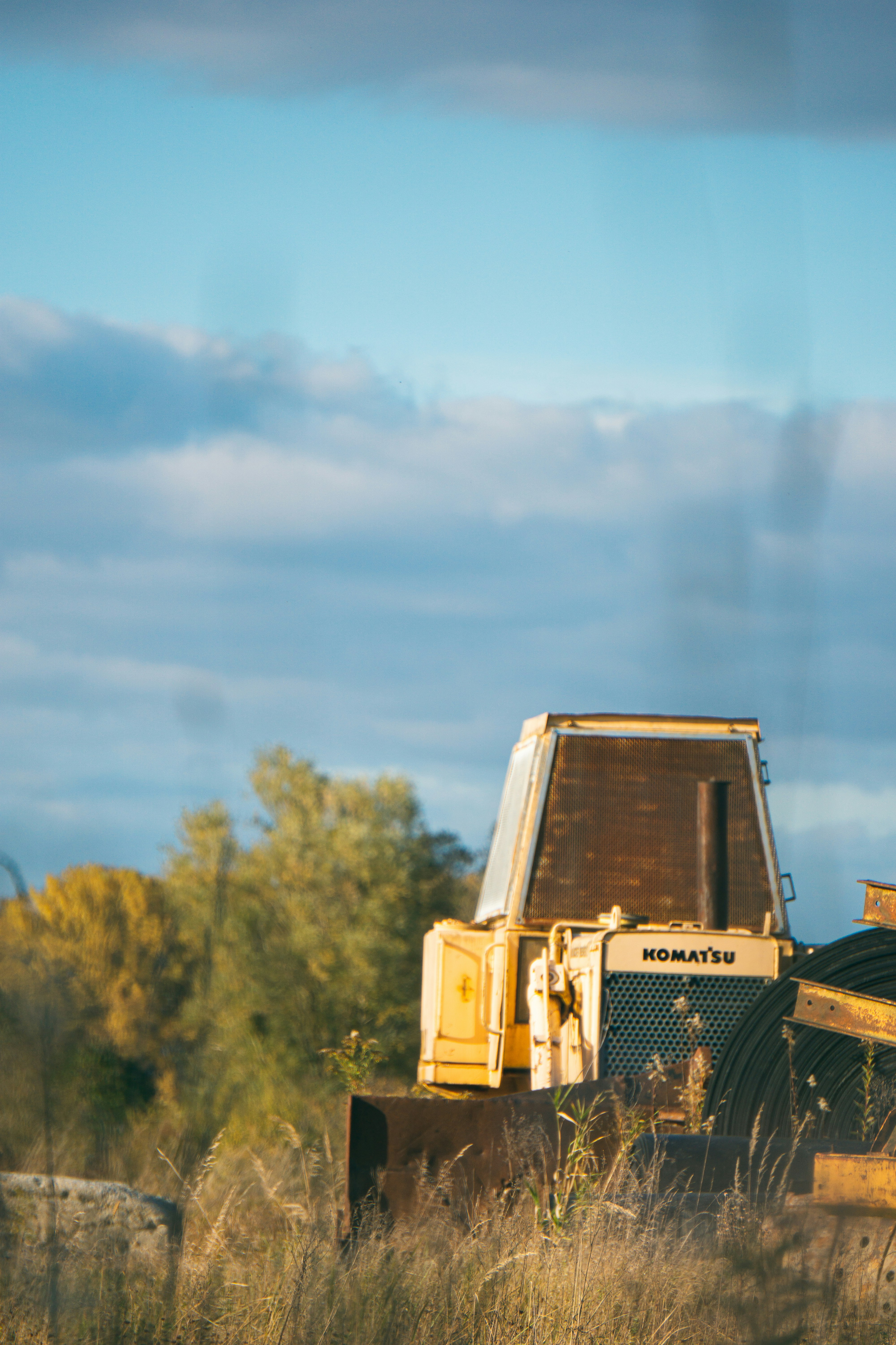 Sunlit Relic: a Komatsu bulldozer resting in a meadow of tall grass