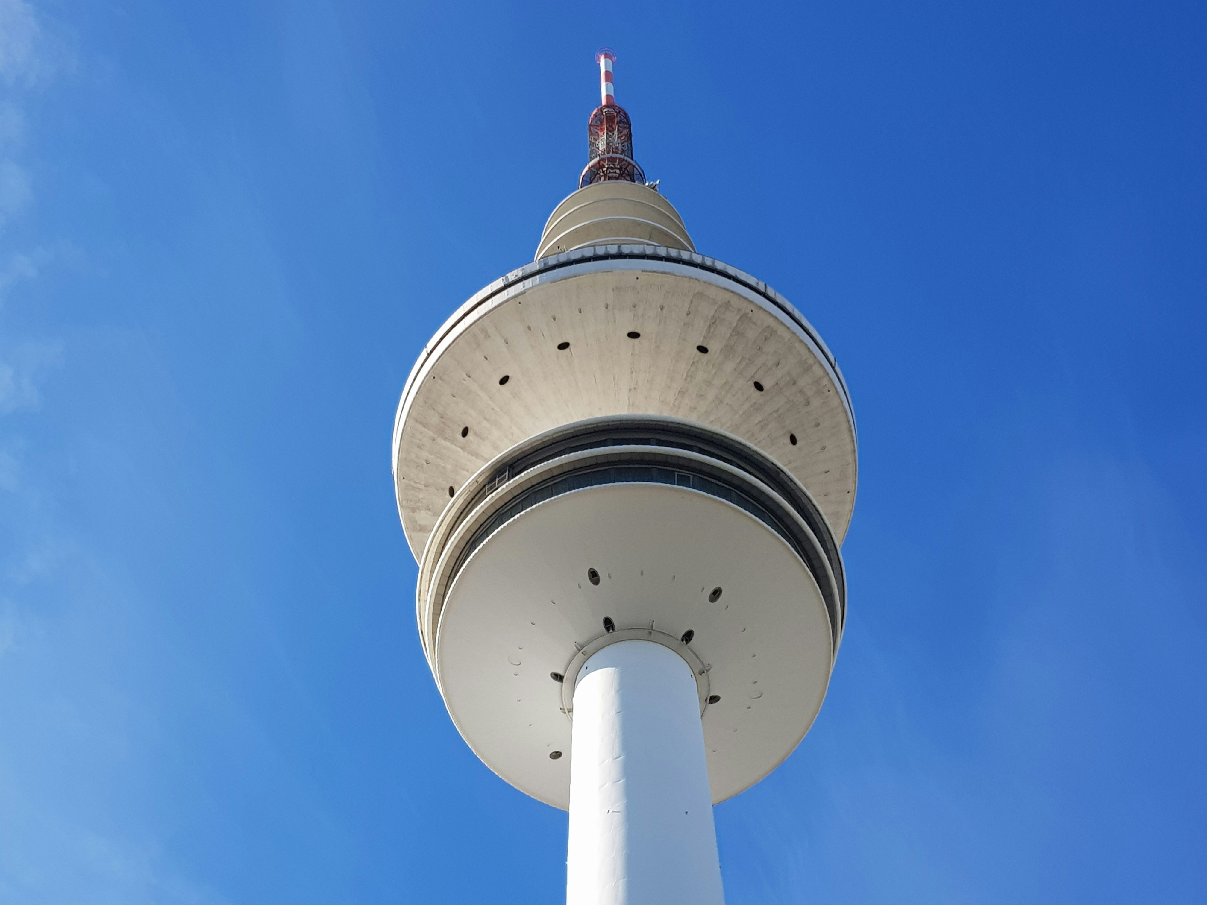 A tall communications tower reaches into the clear blue sky, showcasing its circular structure and observation deck. The image captures the architectural details against a vibrant backdrop.