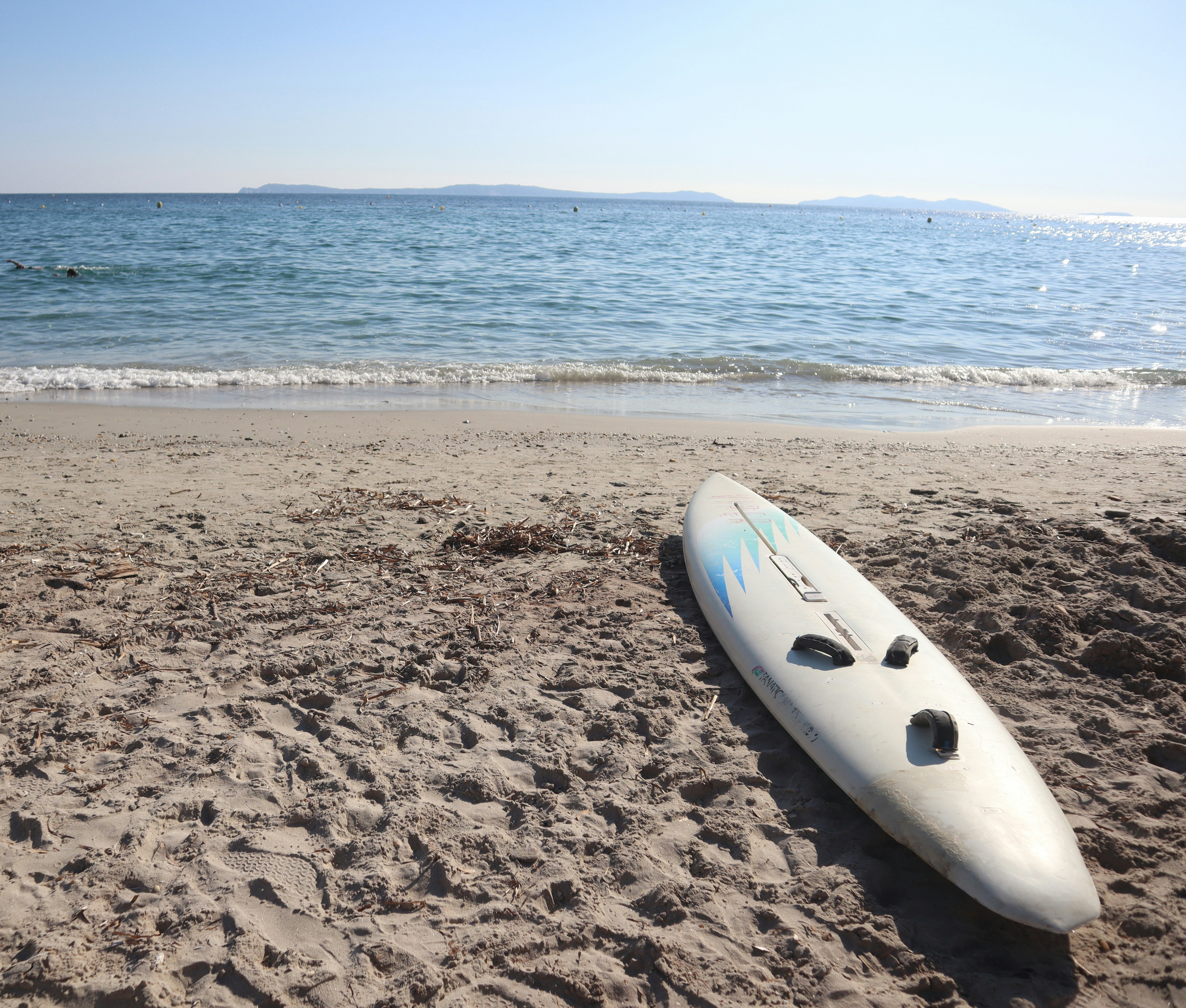a surfboard laying on the sand at the beach