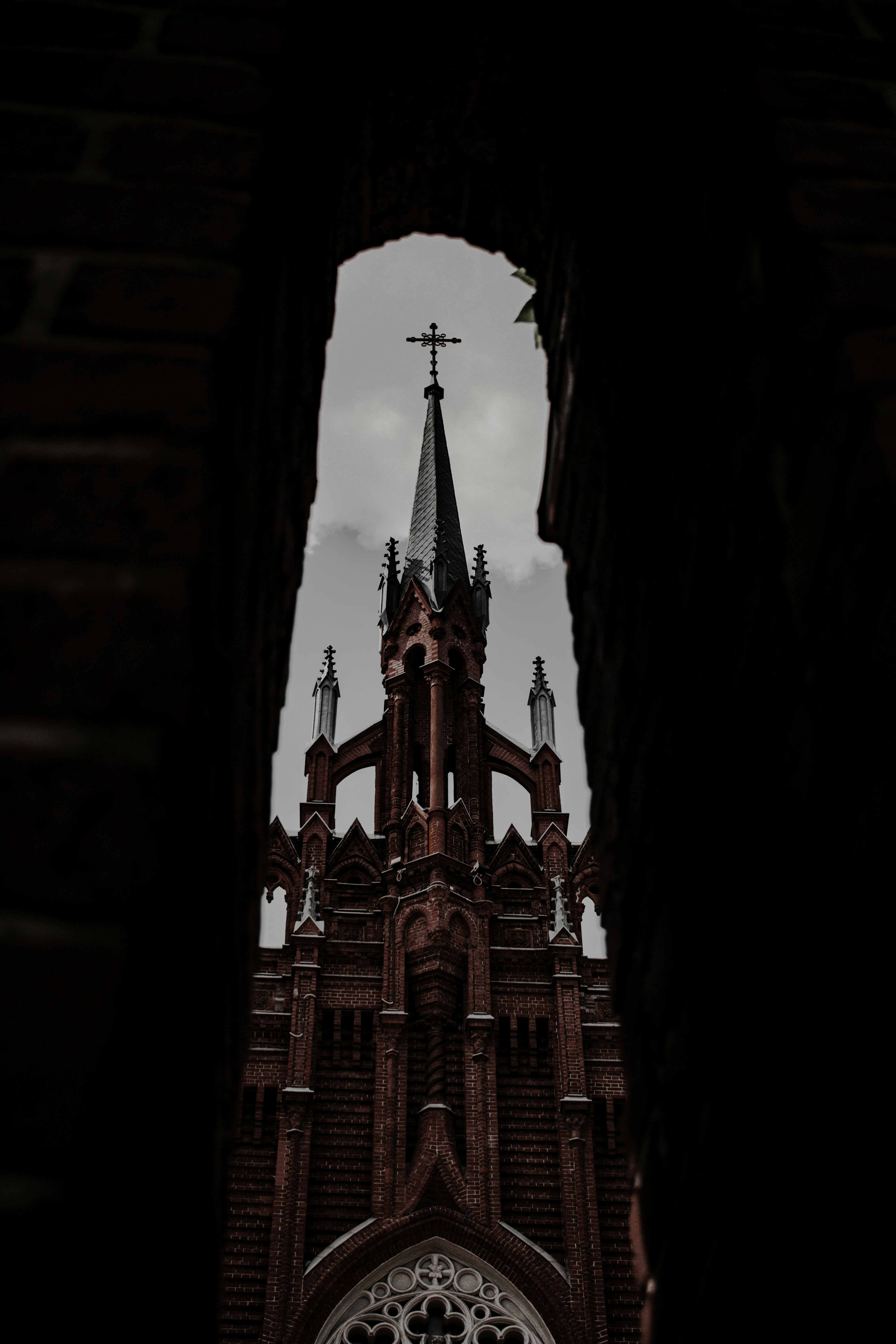 A church with a steeple seen through a hole in the wall photo – Free ...