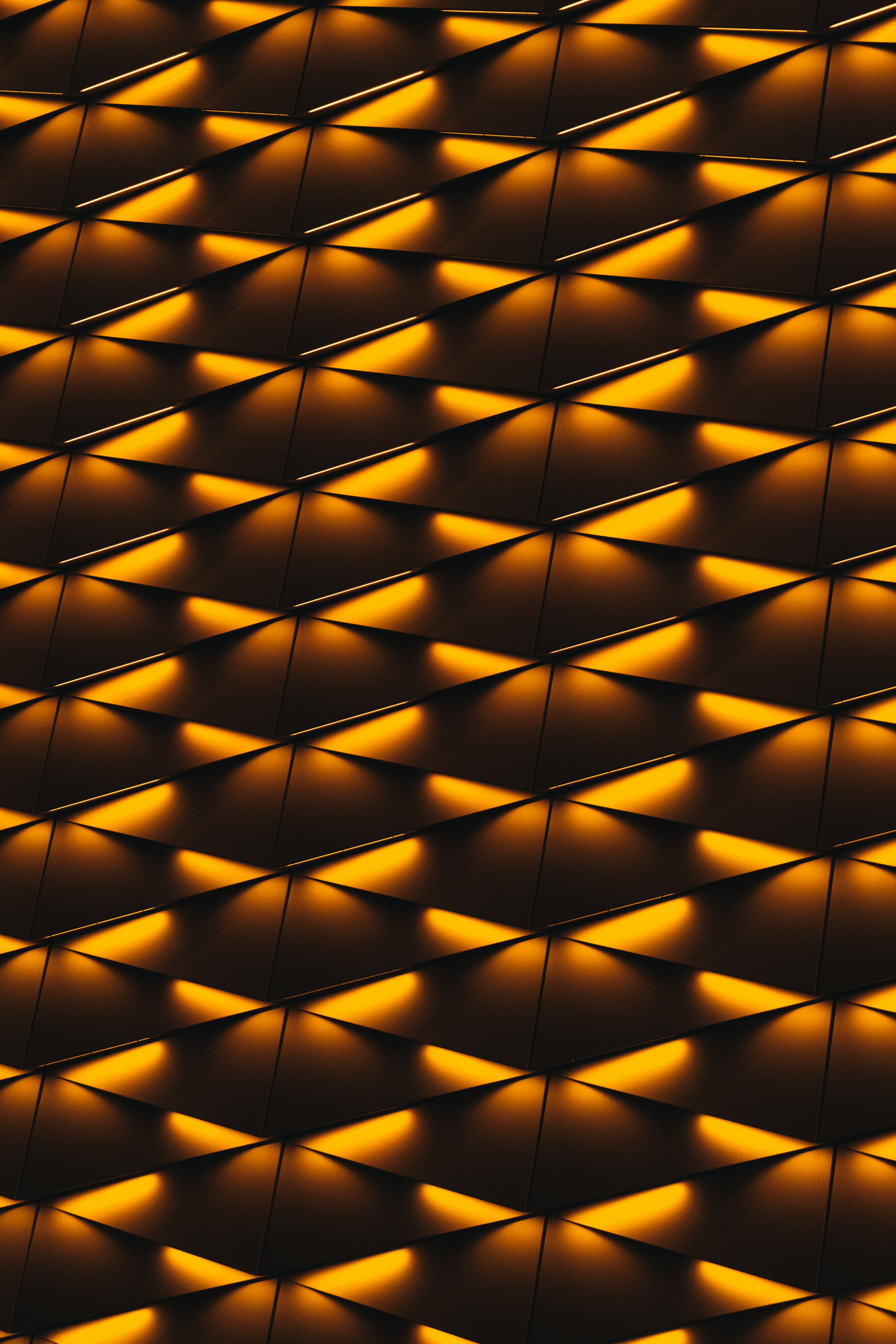 Intricate pattern of illuminated triangular shapes on a textured surface, showcasing a warm golden glow.