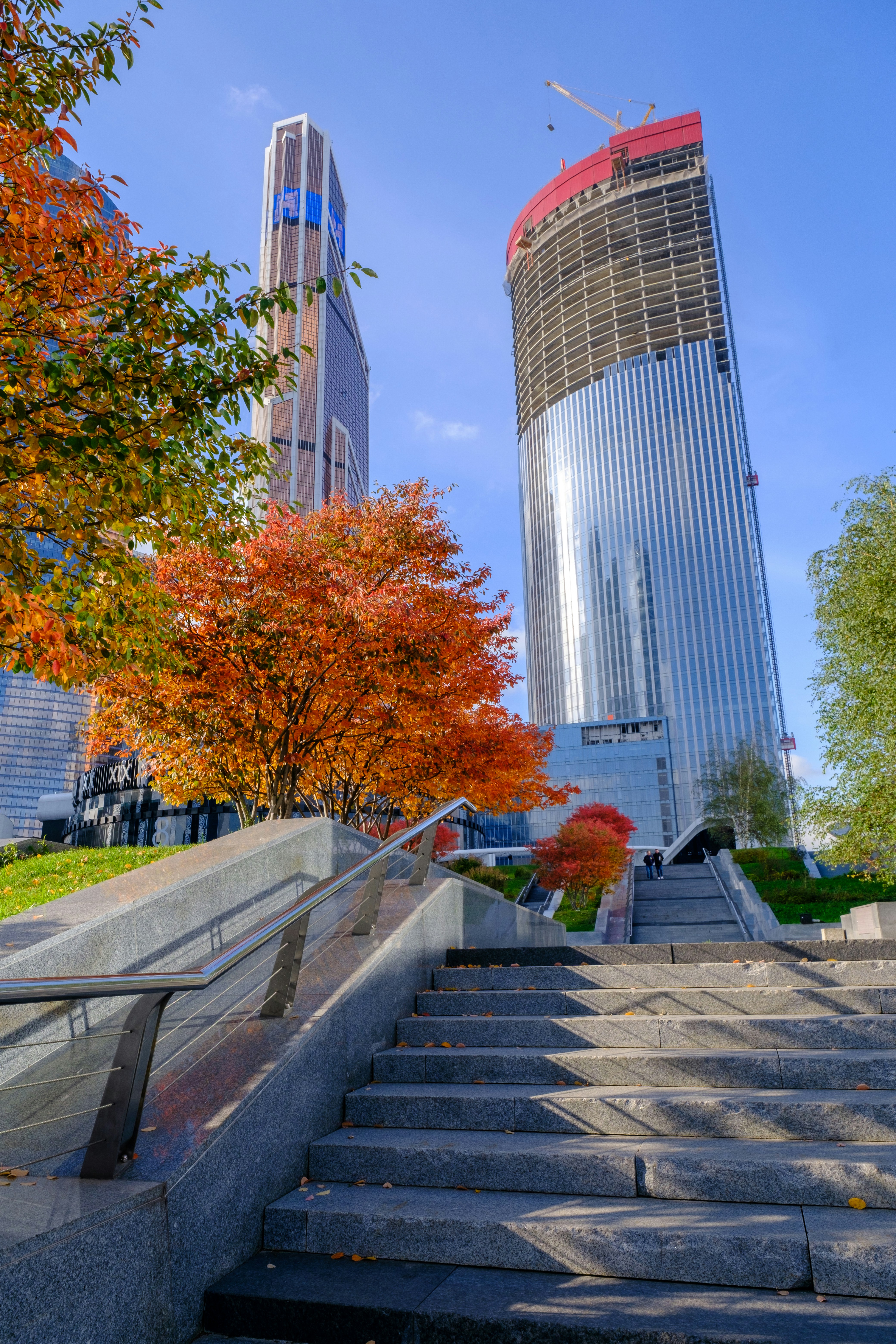 Vibrant autumn foliage contrasts with sleek skyscrapers, showcasing a blend of nature and architecture. The scene captures the essence of urban life in a changing season.