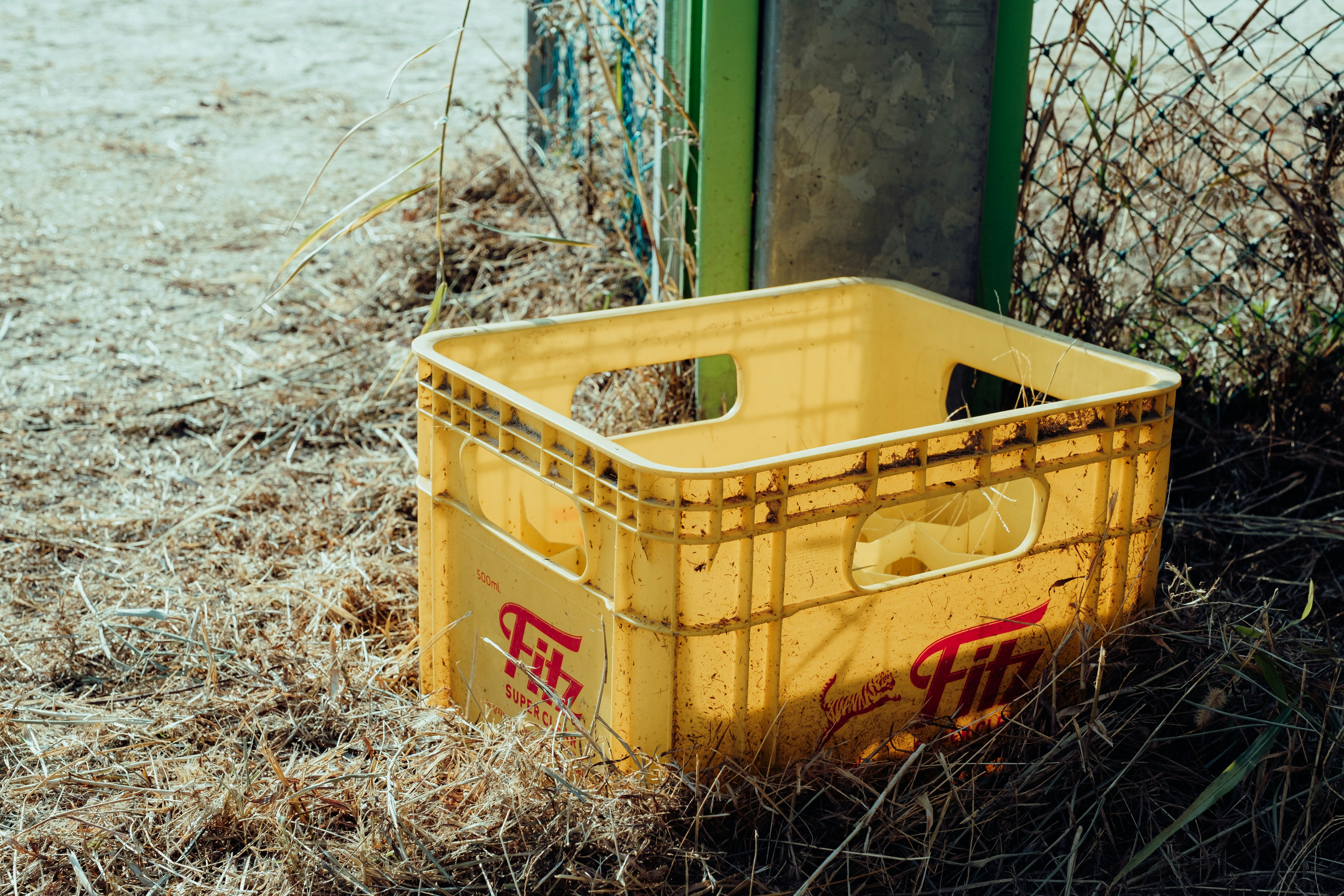 A yellow crate sitting in the grass next to a fence photo – Free Hanam ...