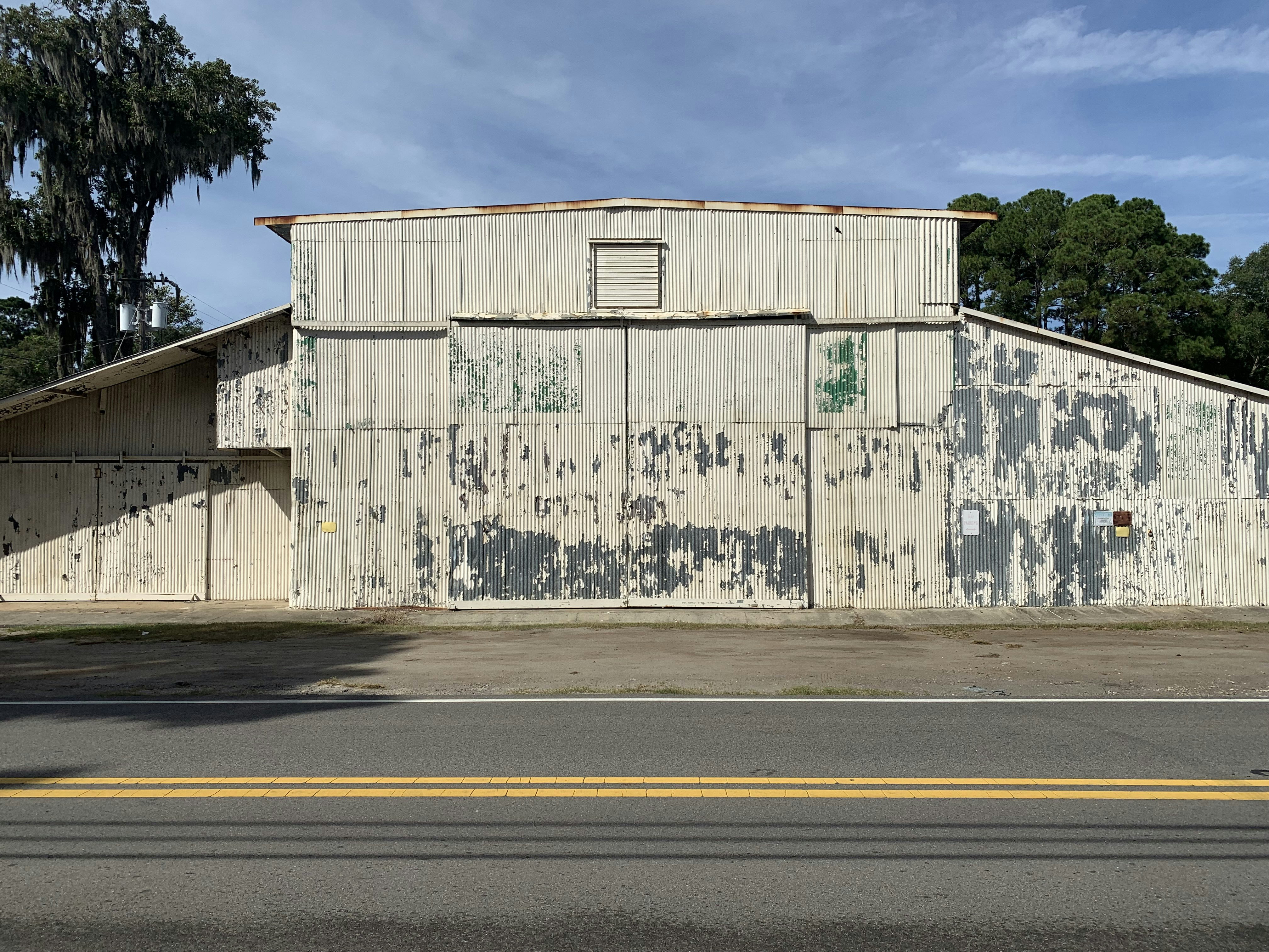 Patina Under Sun: Weathered Warehouse Along a Quiet Road