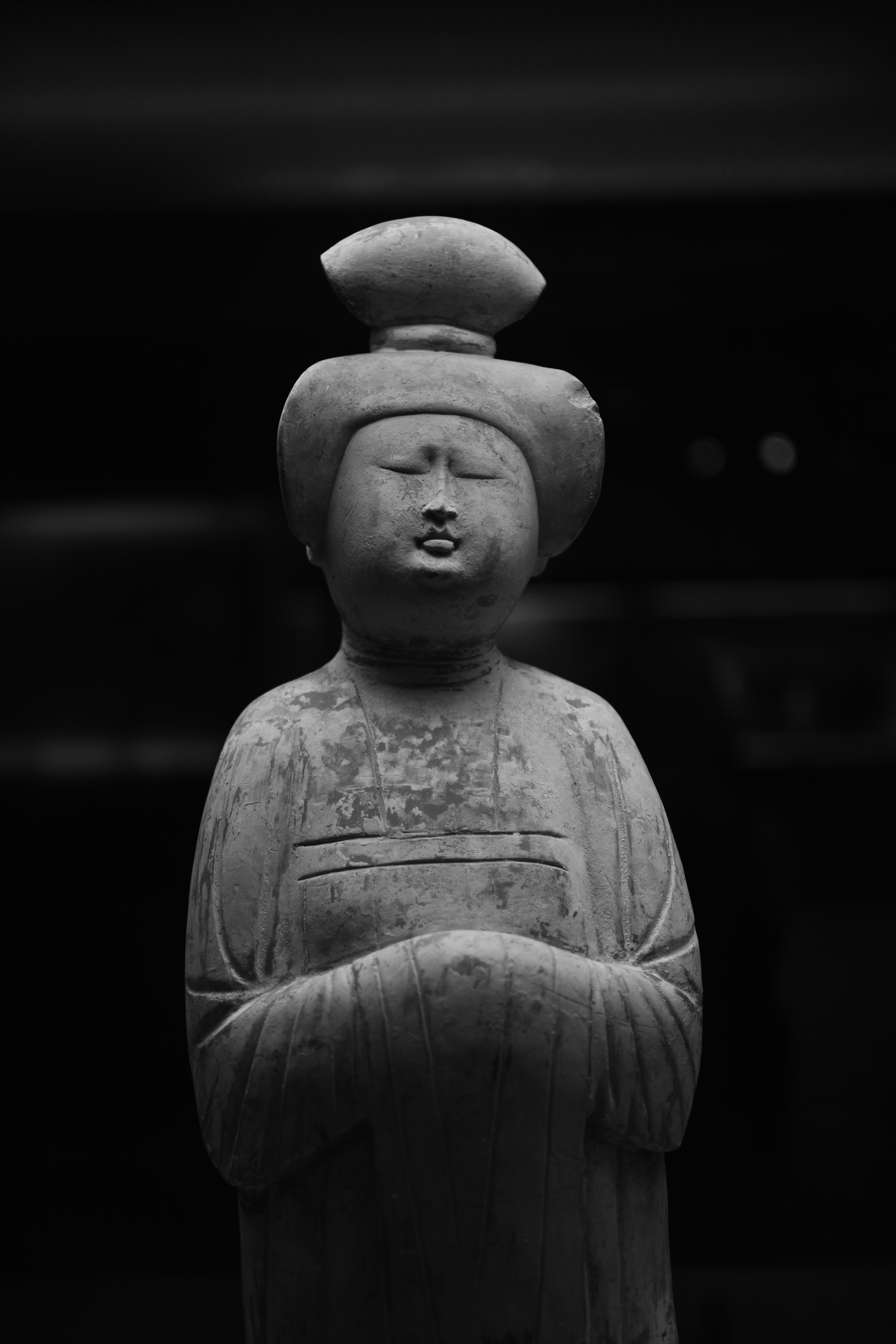 A serene ancient statue with a tranquil expression, hands clasped in front, evoking a sense of peace and history.