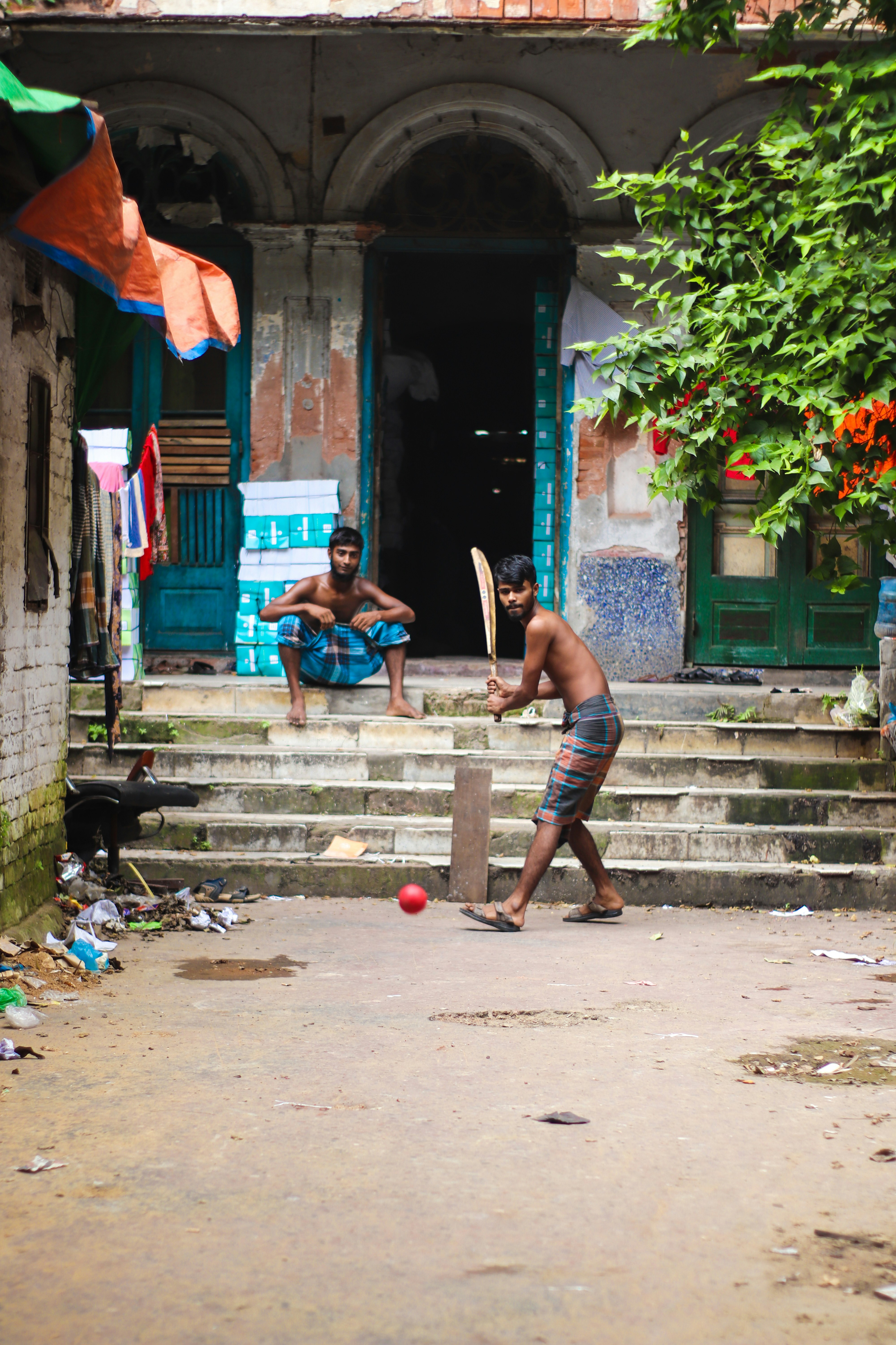 A man playing a game of cricket in front of a building photo – Free ...