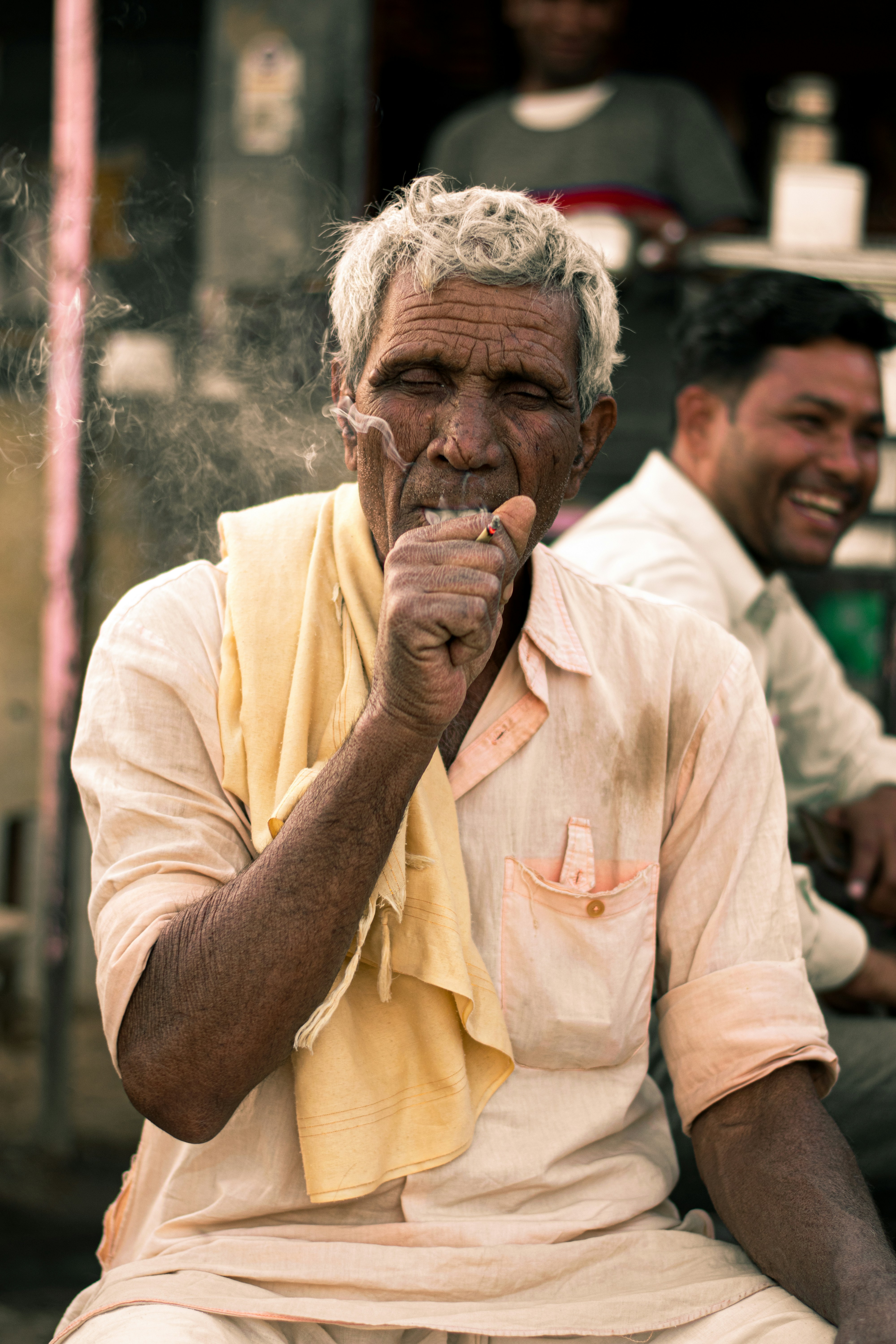 A man sitting down smoking a cigarette photo – Free Man Image on Unsplash