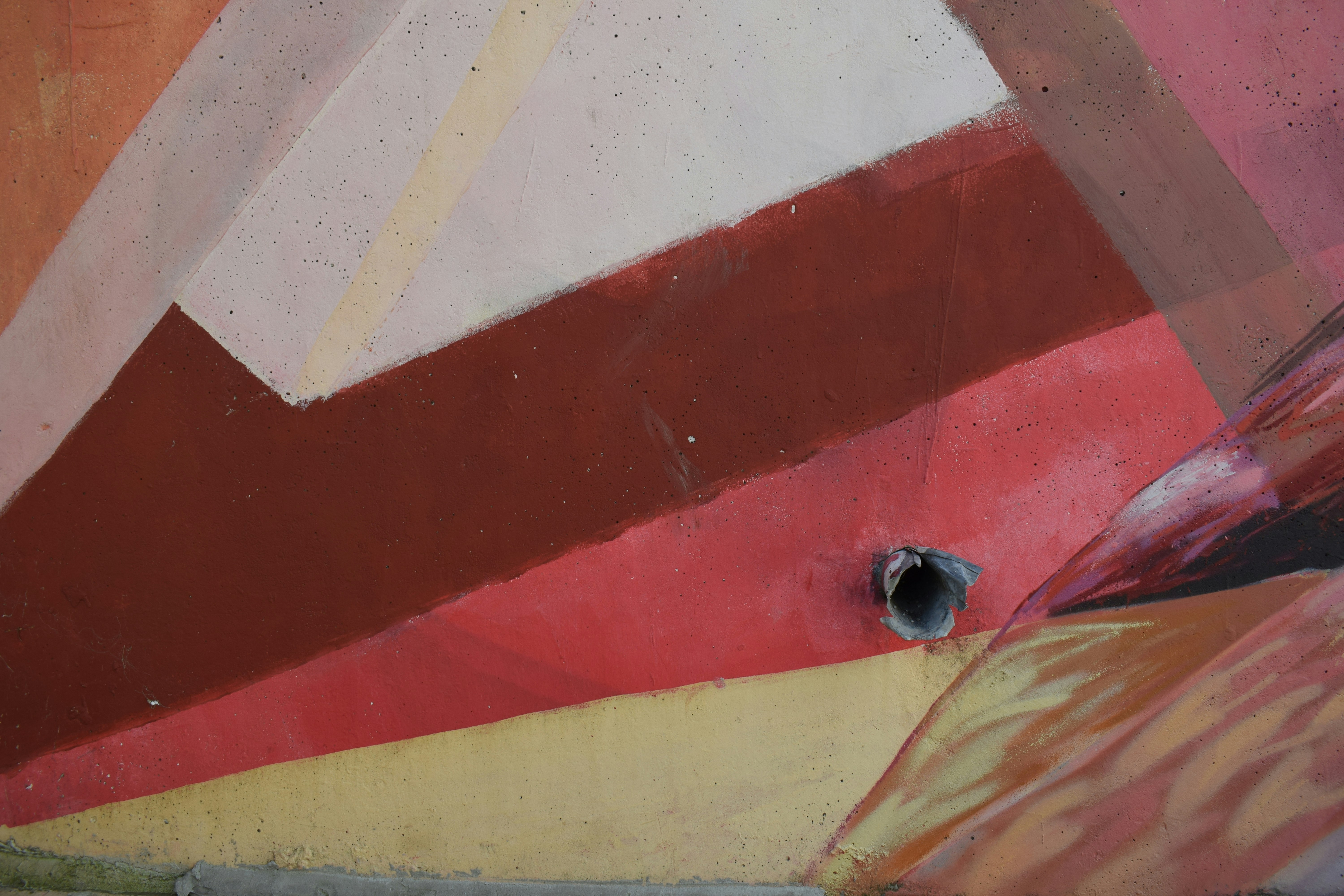 Abstract mural featuring geometric shapes and vibrant colors on a concrete wall.