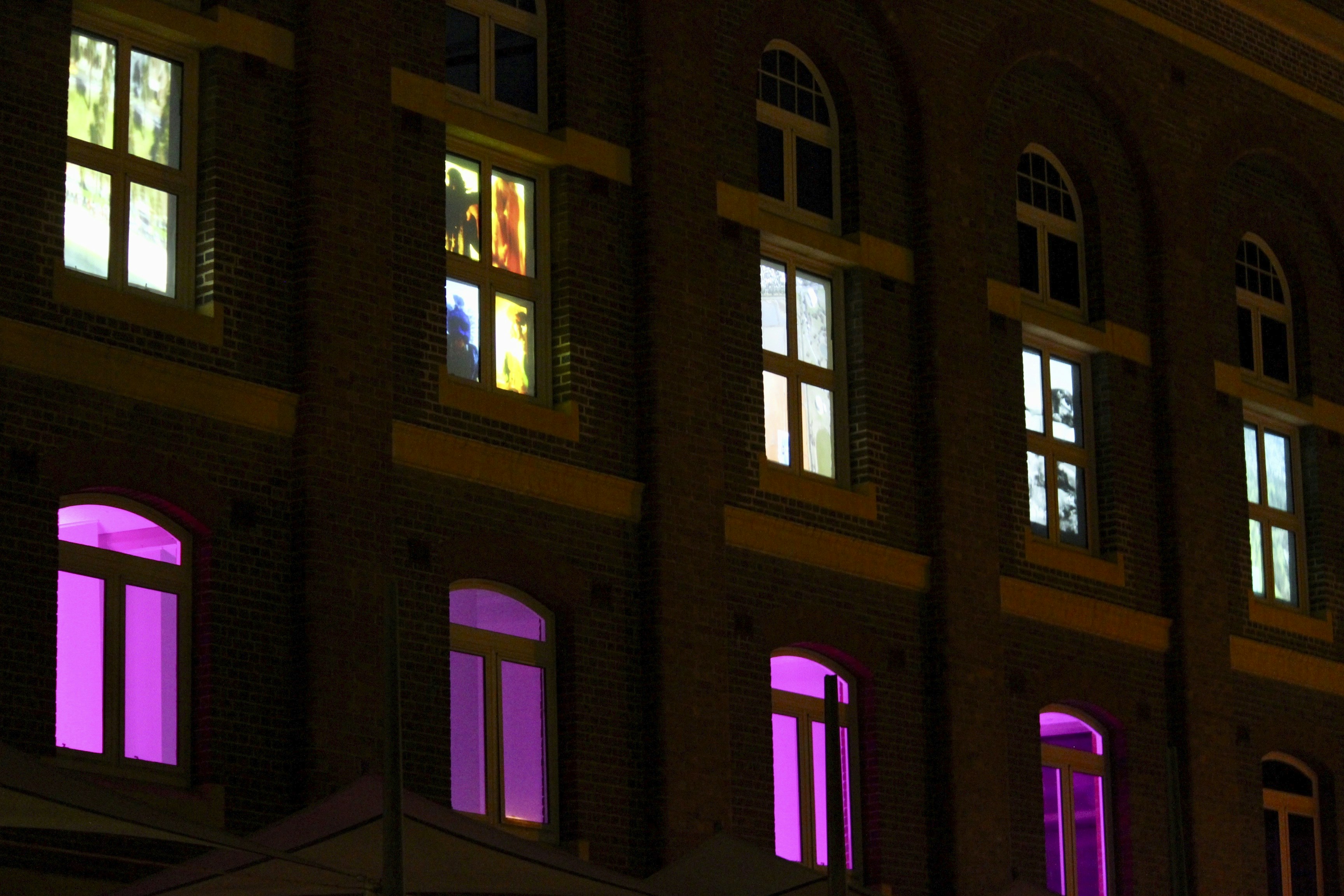 Illuminated building windows displaying a spectrum of colors against the night sky.