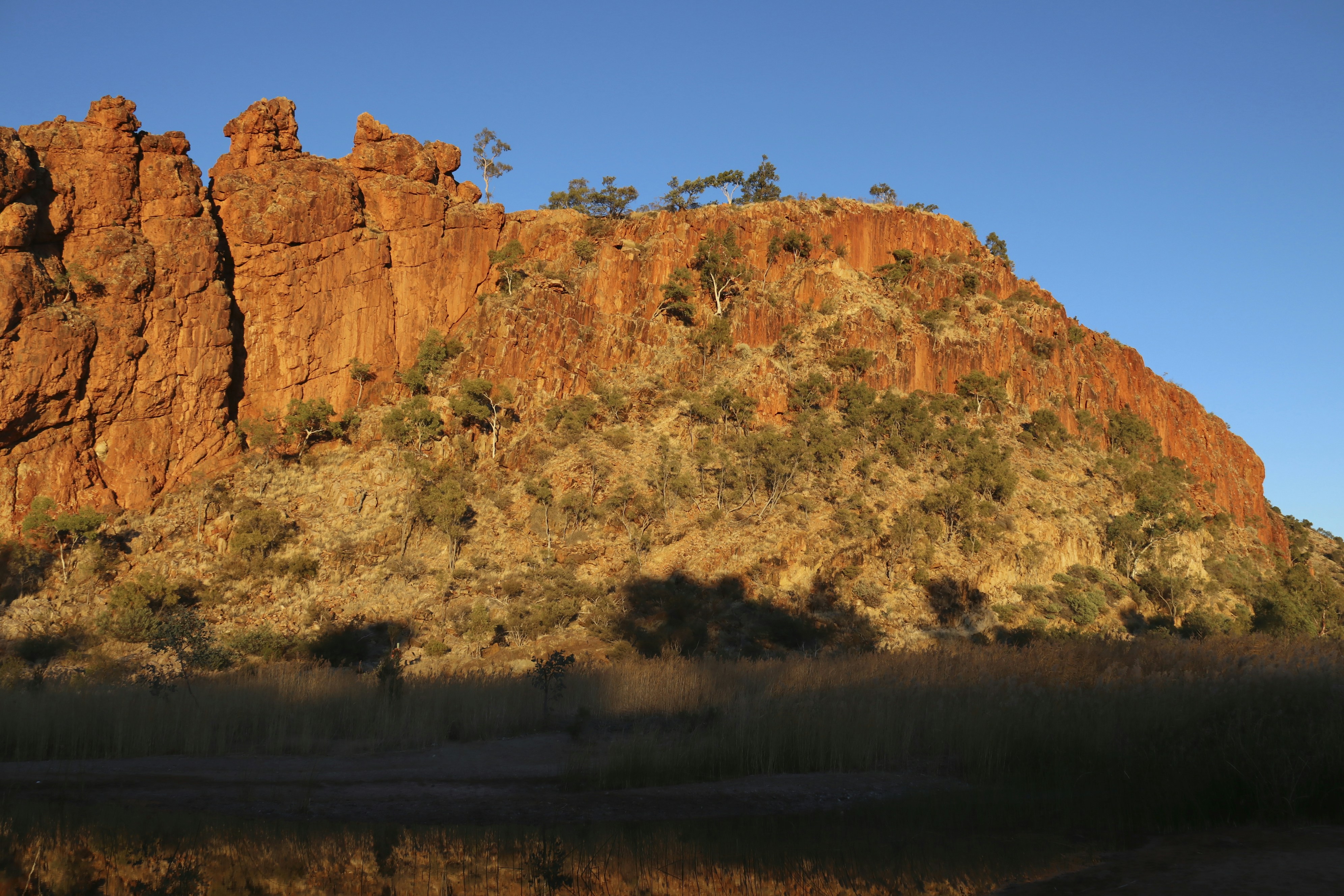 Sunlit Crimson Cliff: A Desert Rock Face in Dusk Light