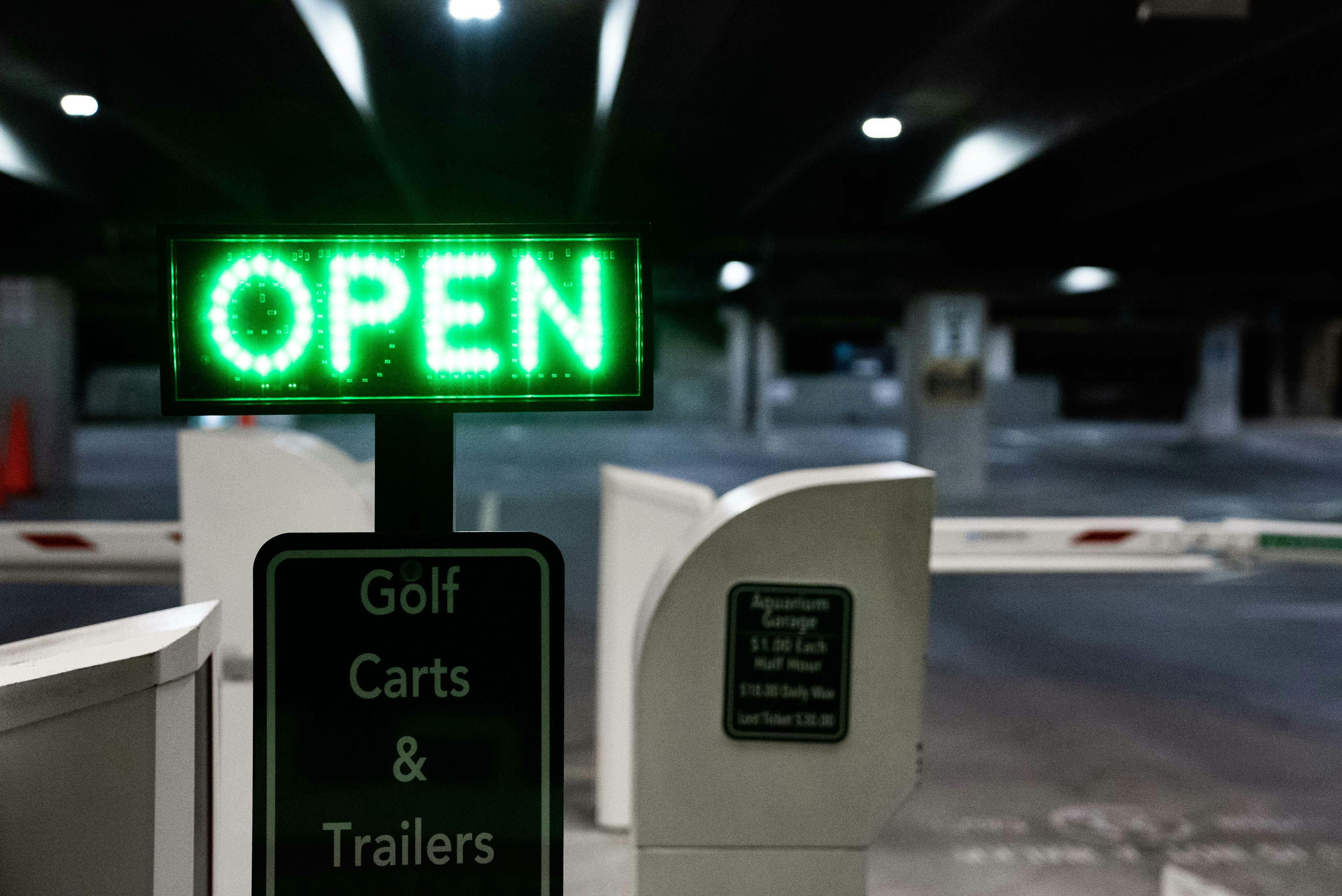 Neon OPEN Sign Casts Green Glow Across a Quiet Indoor Parking Gate