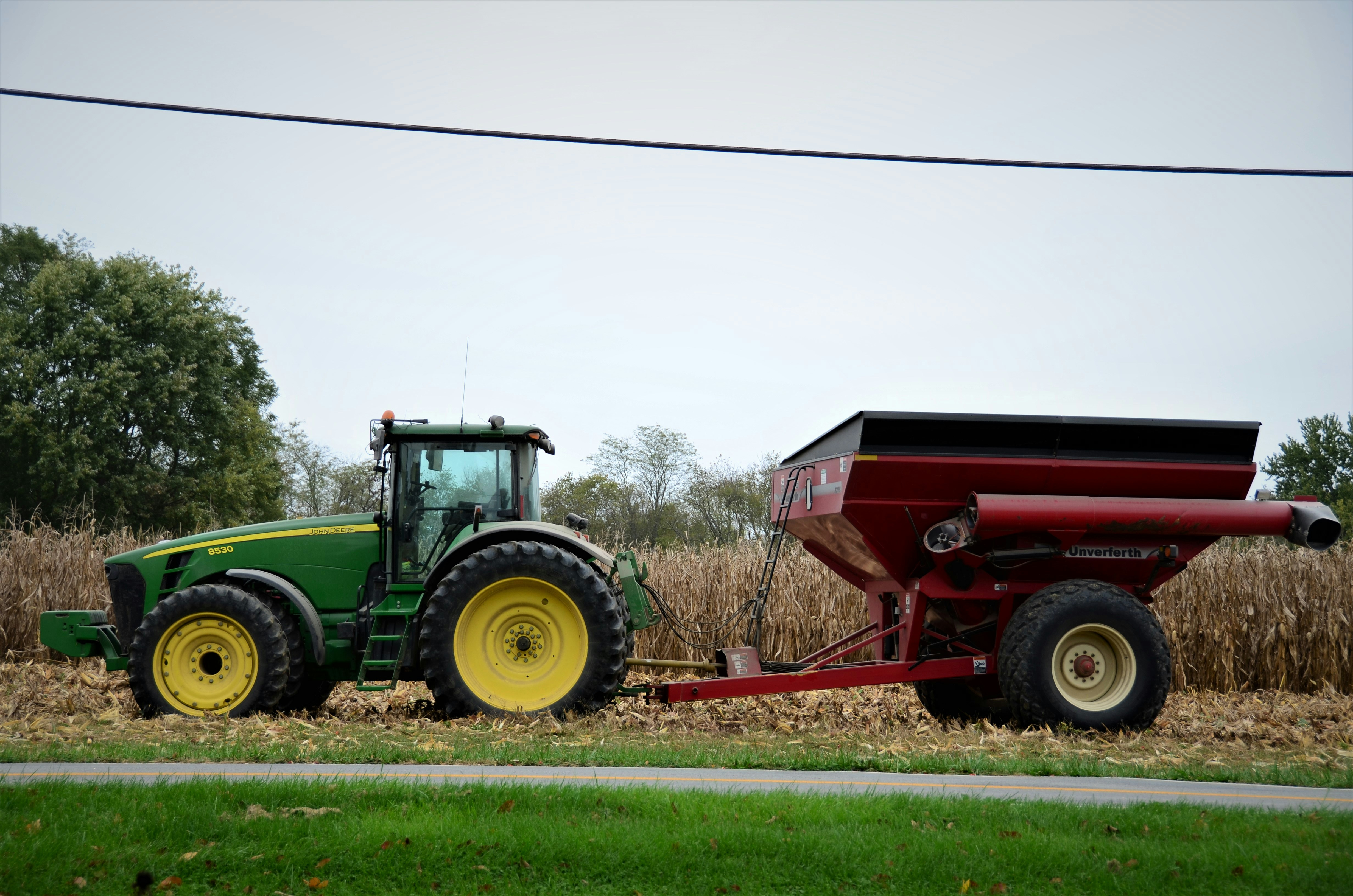 A tractor pulling a trailer behind it in a field photo – Free Nature ...