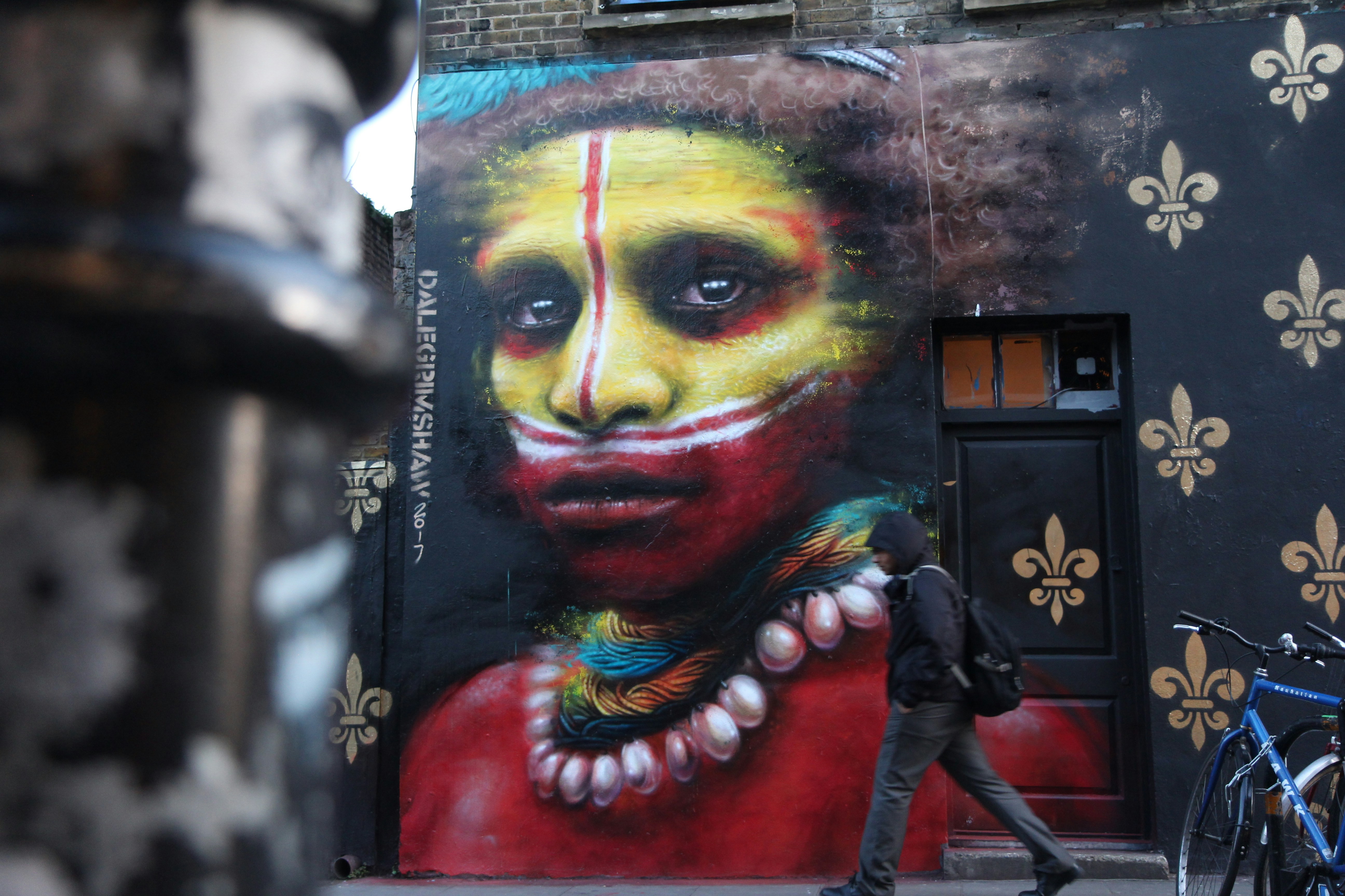 Gilded Gaze by the Red Door: A Street Portrait on Brick