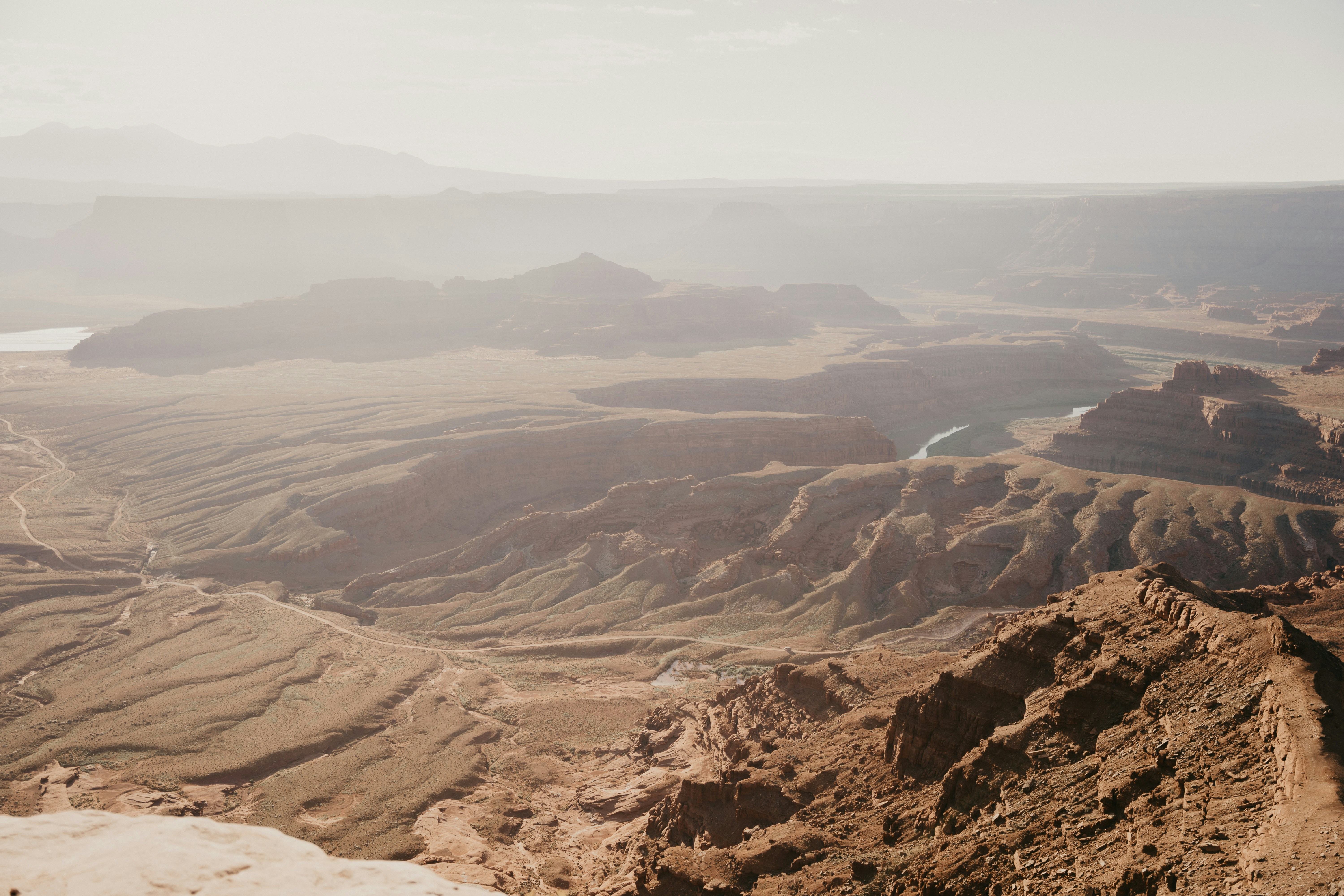 Expansive desert valley with layered rock formations under soft sunlight.