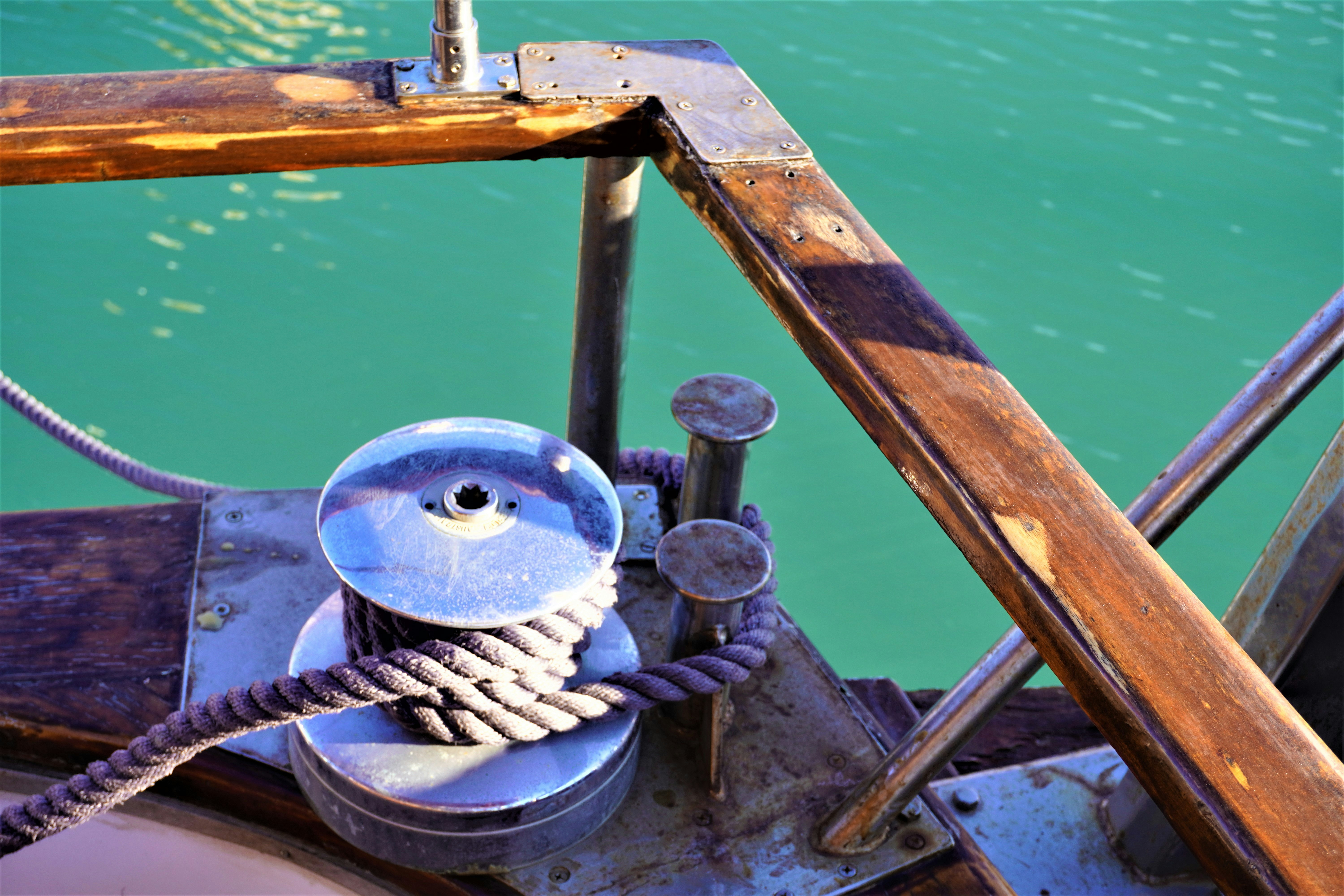 Weathered Winch on a Turquoise Sea Deck: Rope, Wood, and Rust