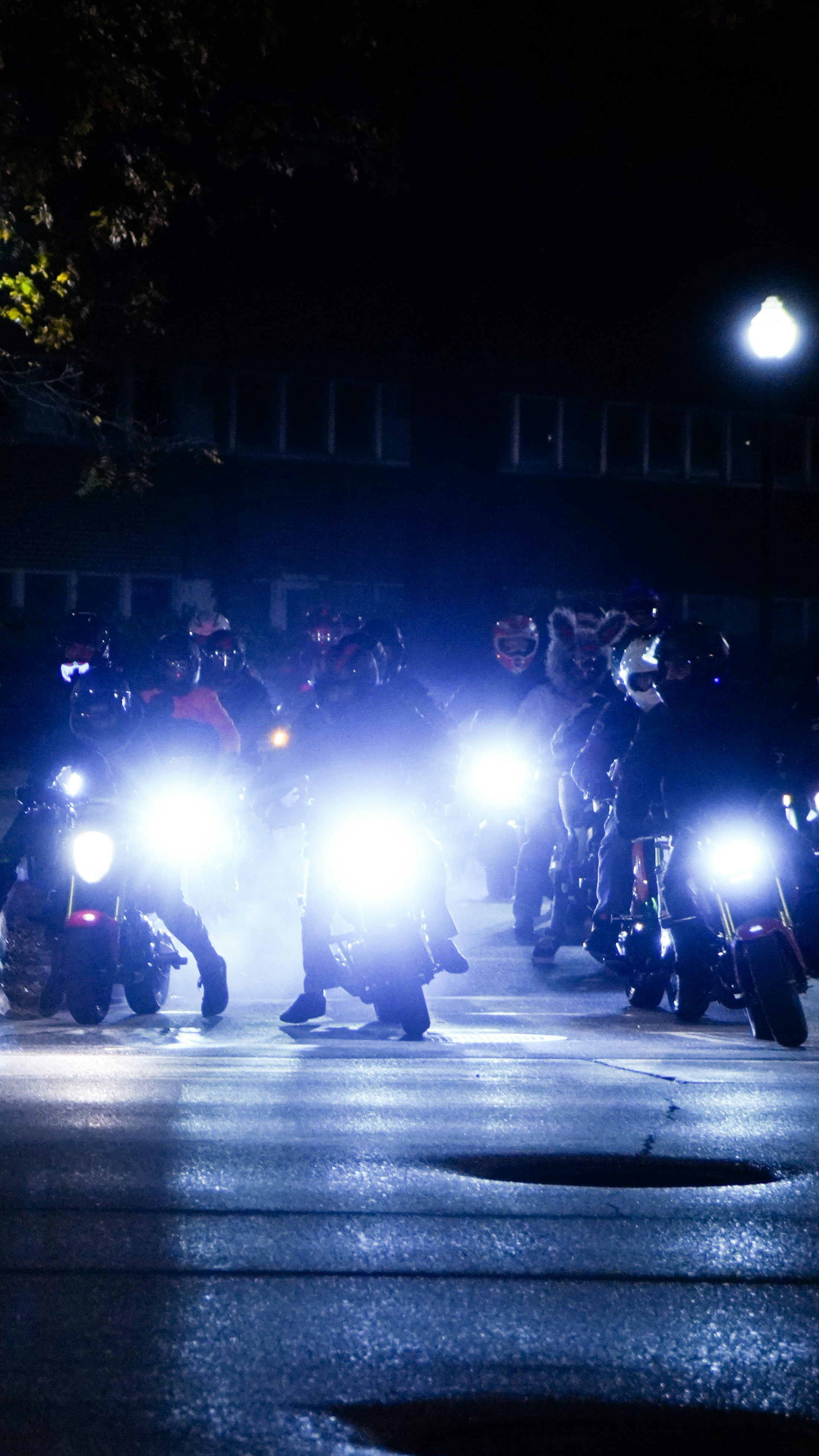 Nocturnal Moto Parade: Neon Headlights Across a Rain-Wet Street