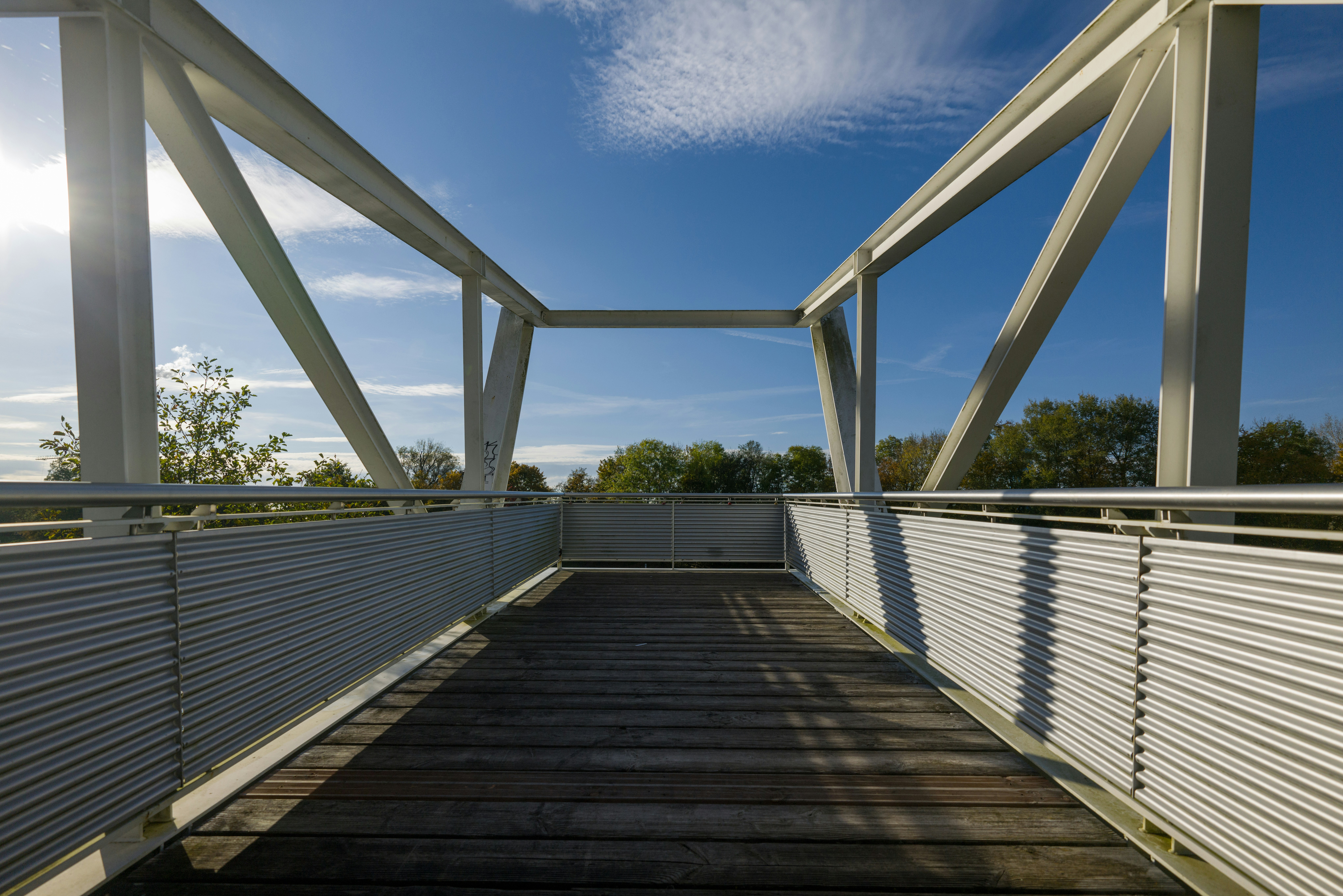 A wooden walkway with a white fence and blue sky in the background ...