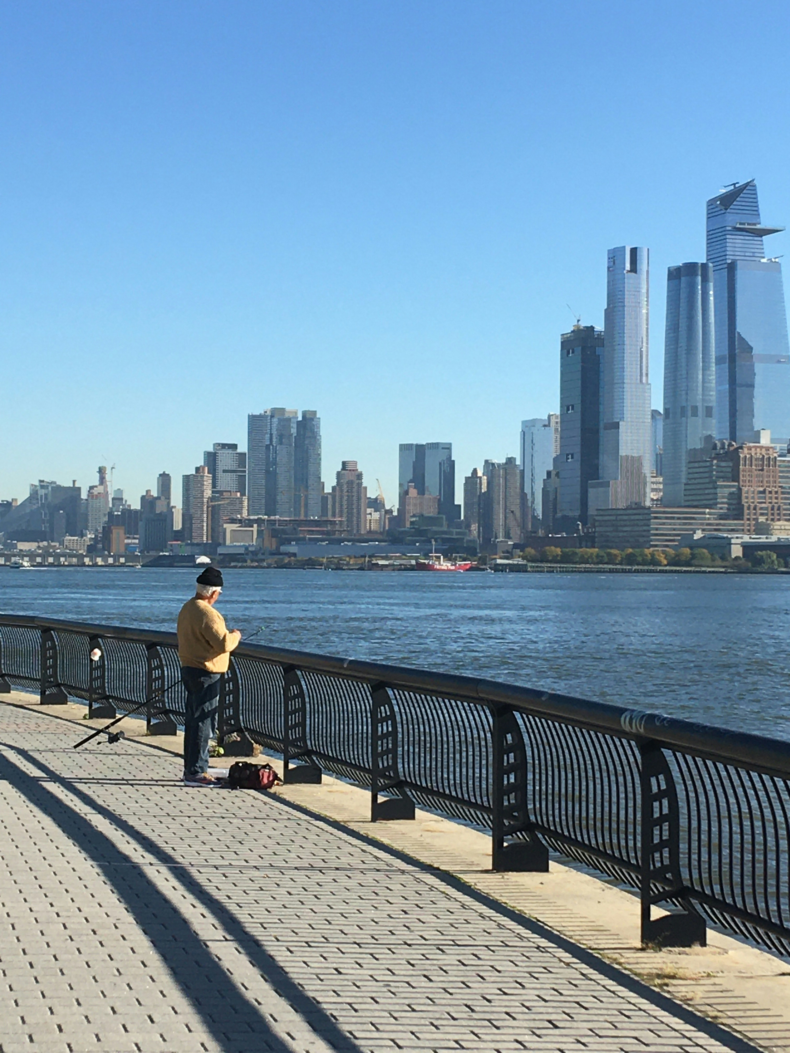 Riverside Fisherman in a Quiet Moment with a Skyscraper Skyline