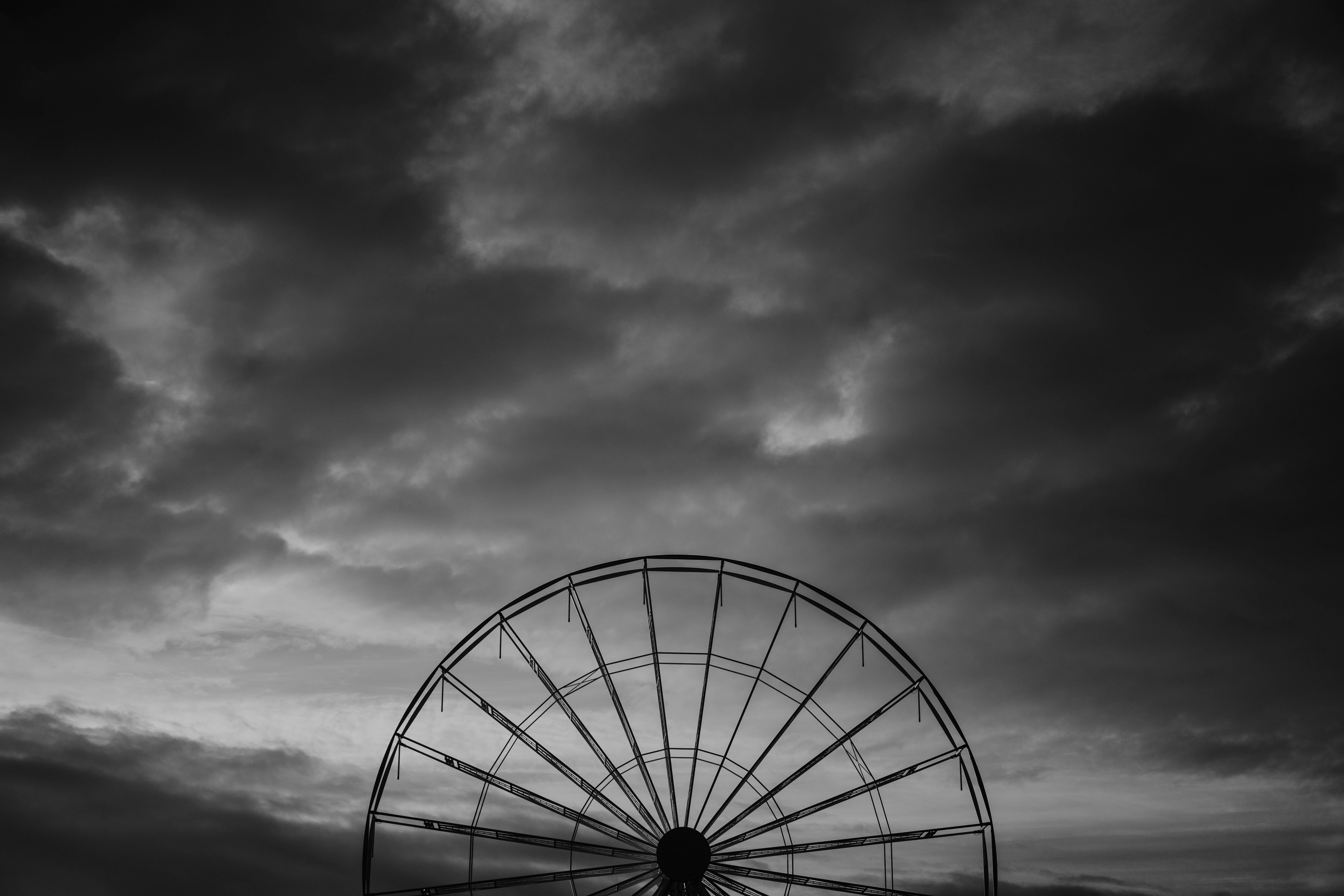 Silhouette of a Ferris Wheel Beneath Heaving Clouds