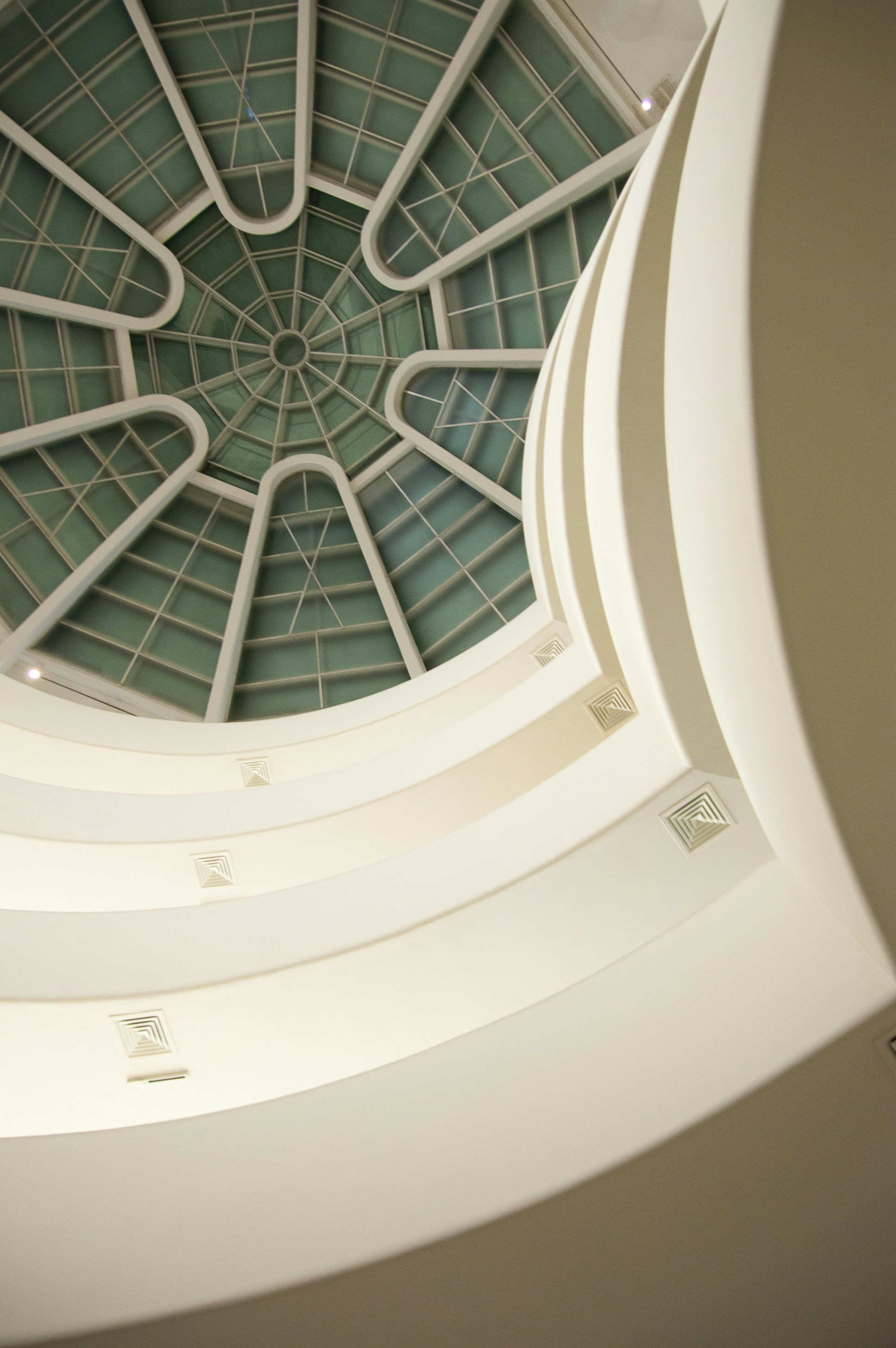 Upward view of a spiral architectural design with a glass dome ceiling.