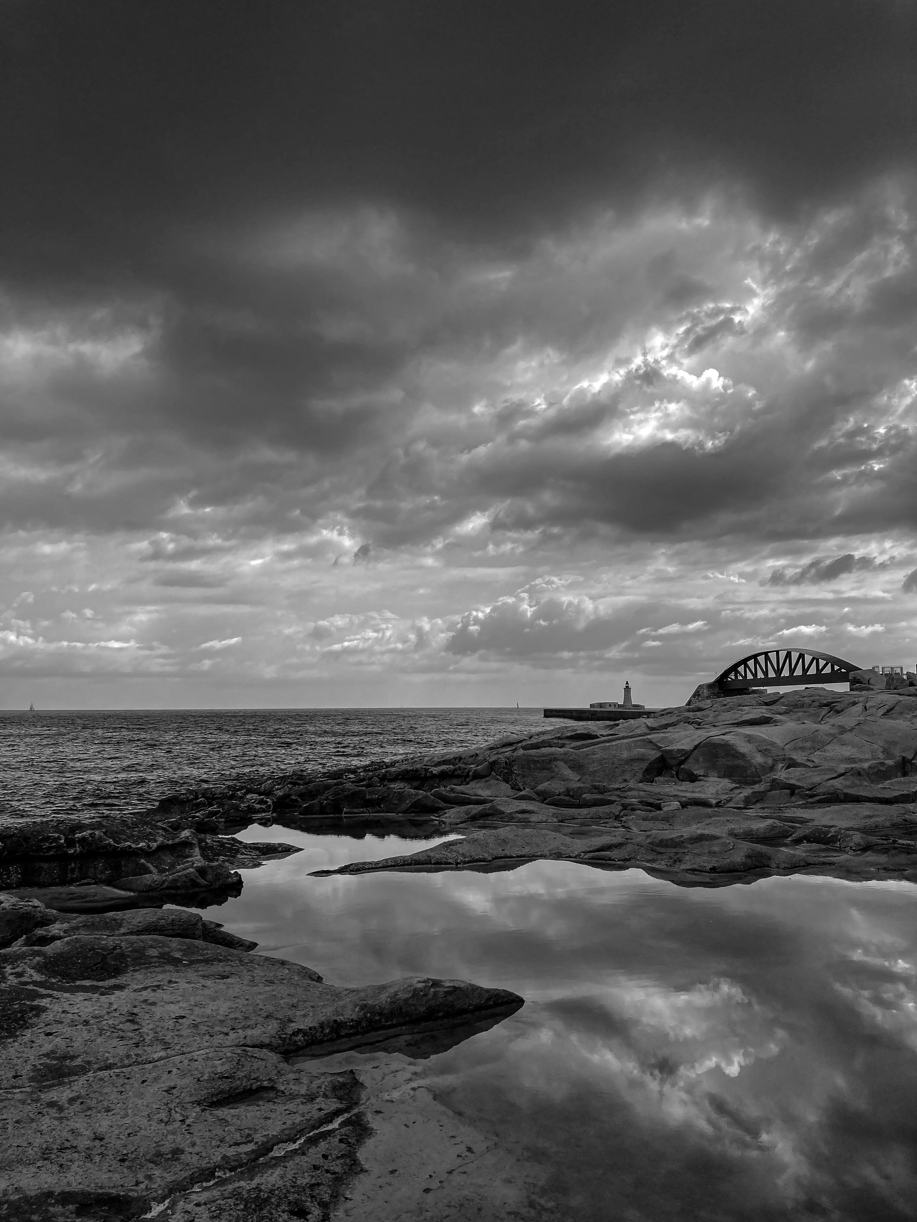 a black and white photo of a bridge and water