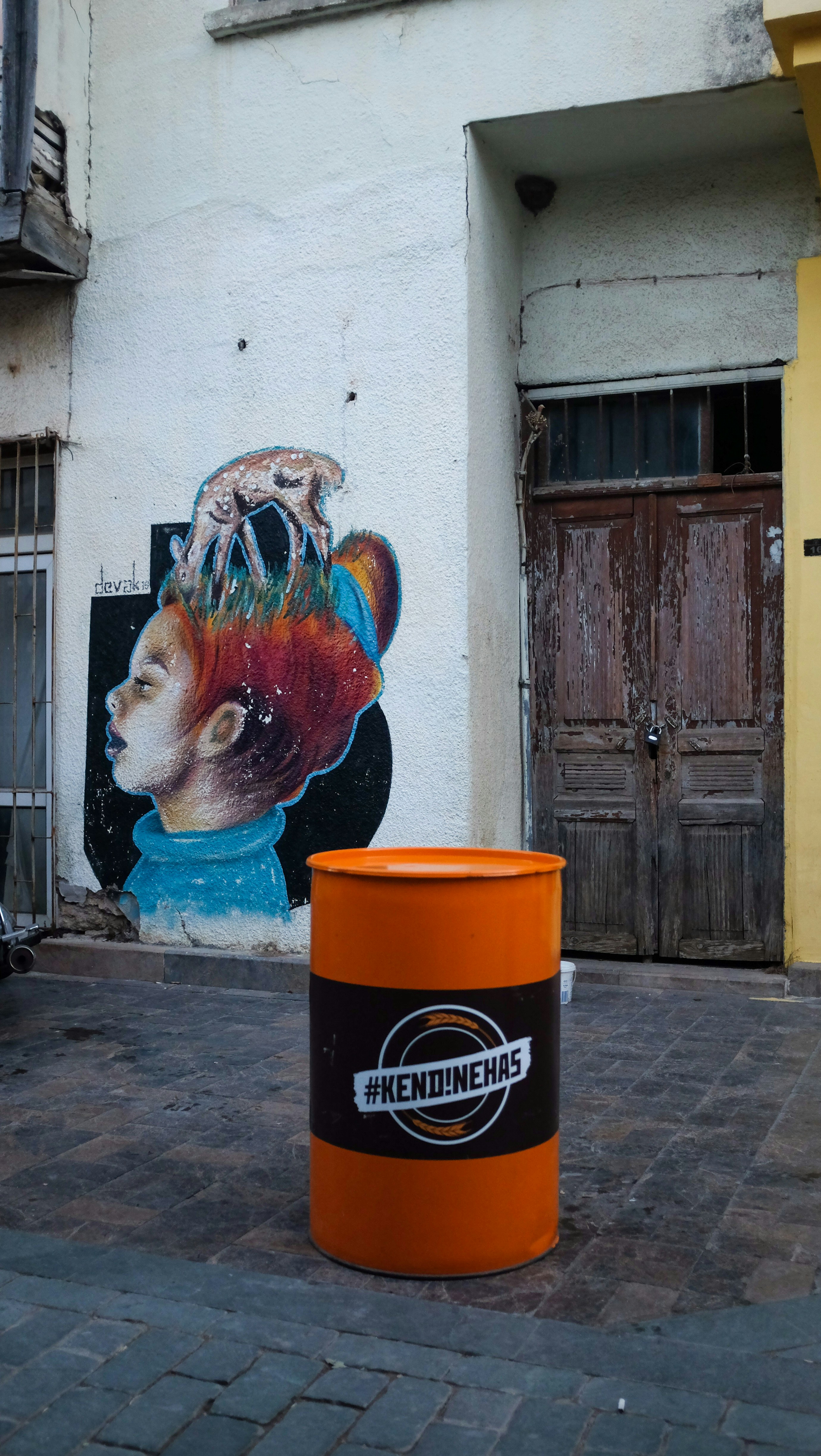 an orange trash can sitting in front of a building