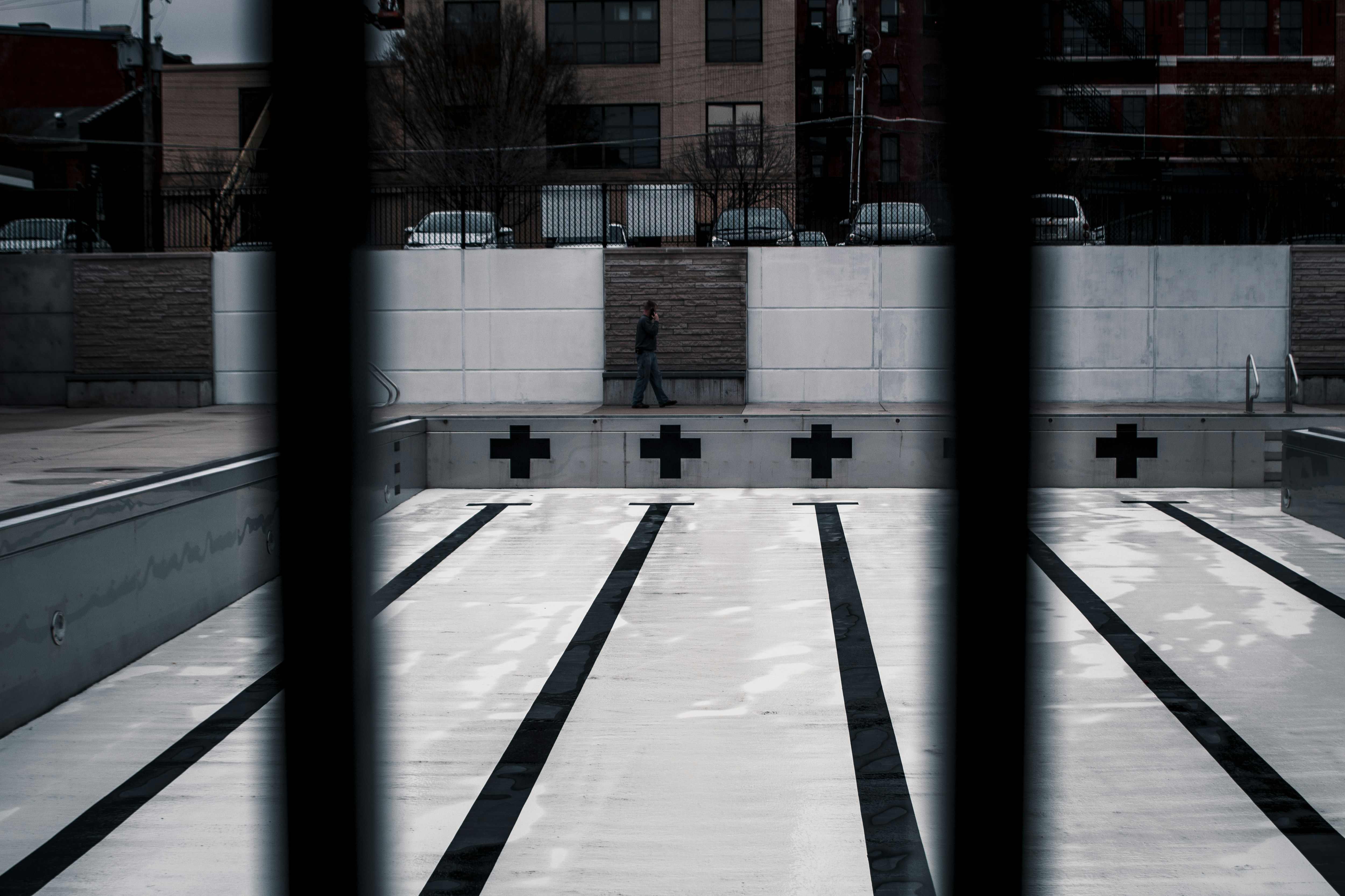 Between Bars and Lanes: A Lone Figure at an Empty Outdoor Pool