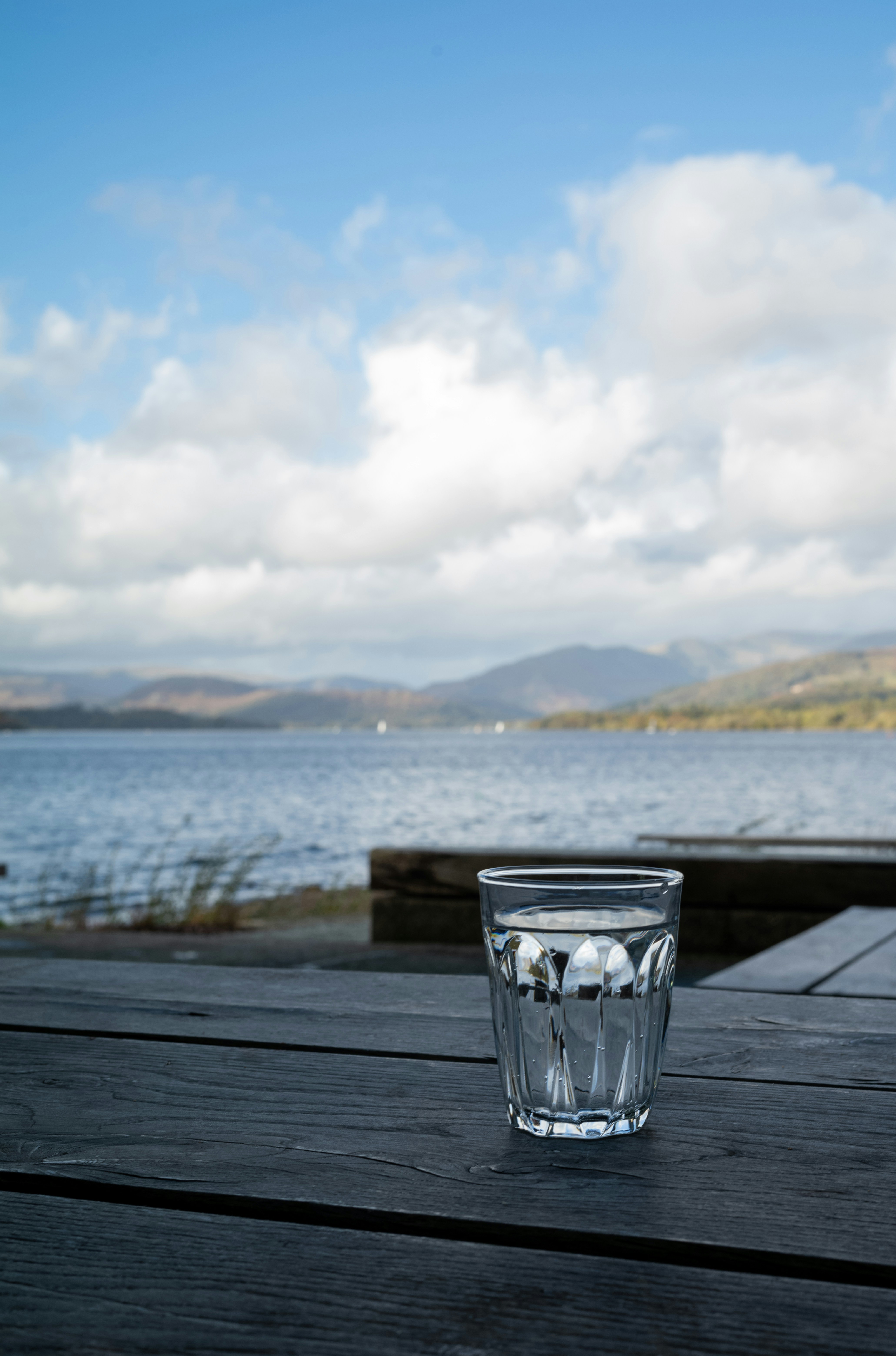 Crystal Clear Stillness: A Glass on Weathered Wood by the Lake