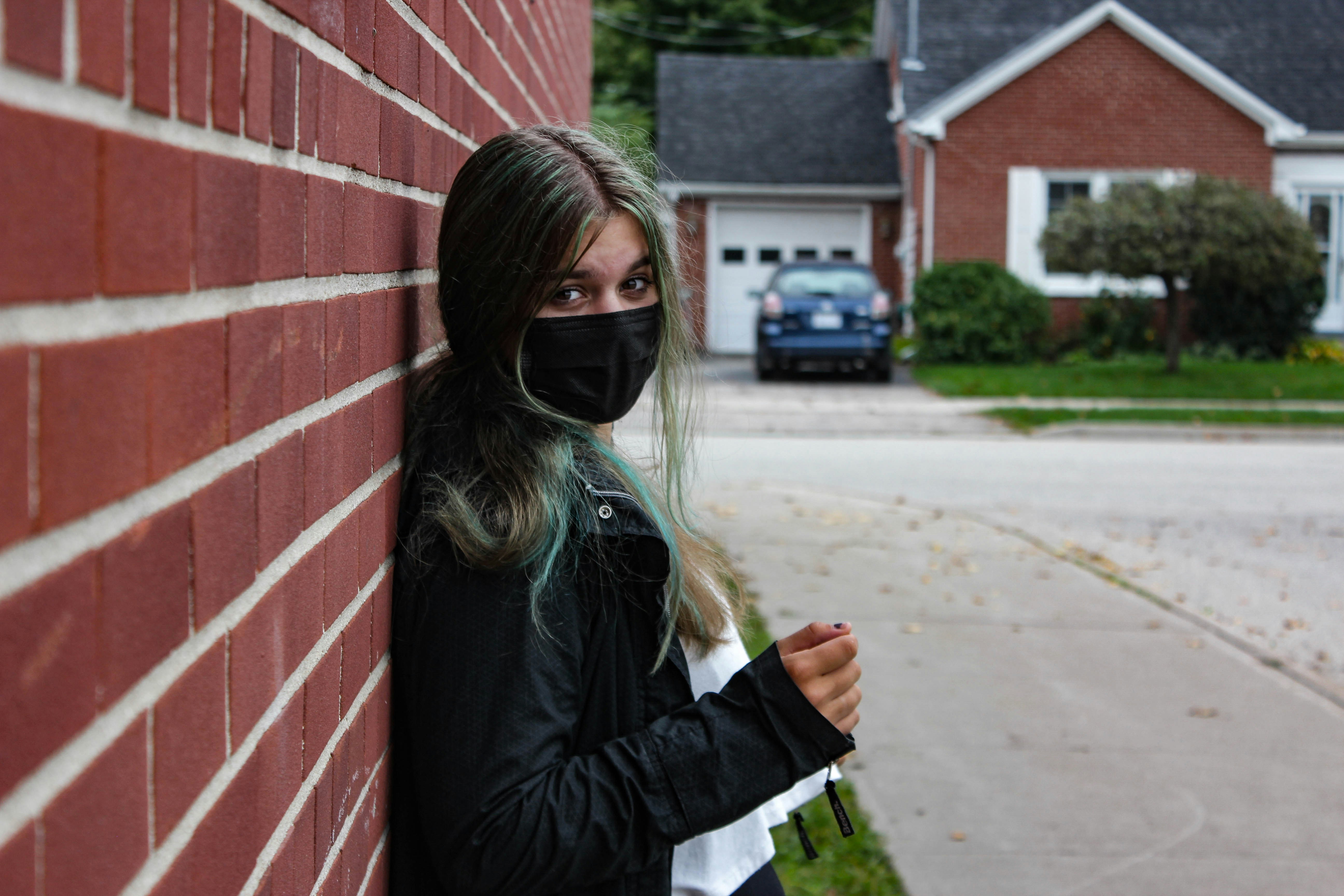 Mask and Brick: A Quiet Moment of Vigilance on the Street Edge