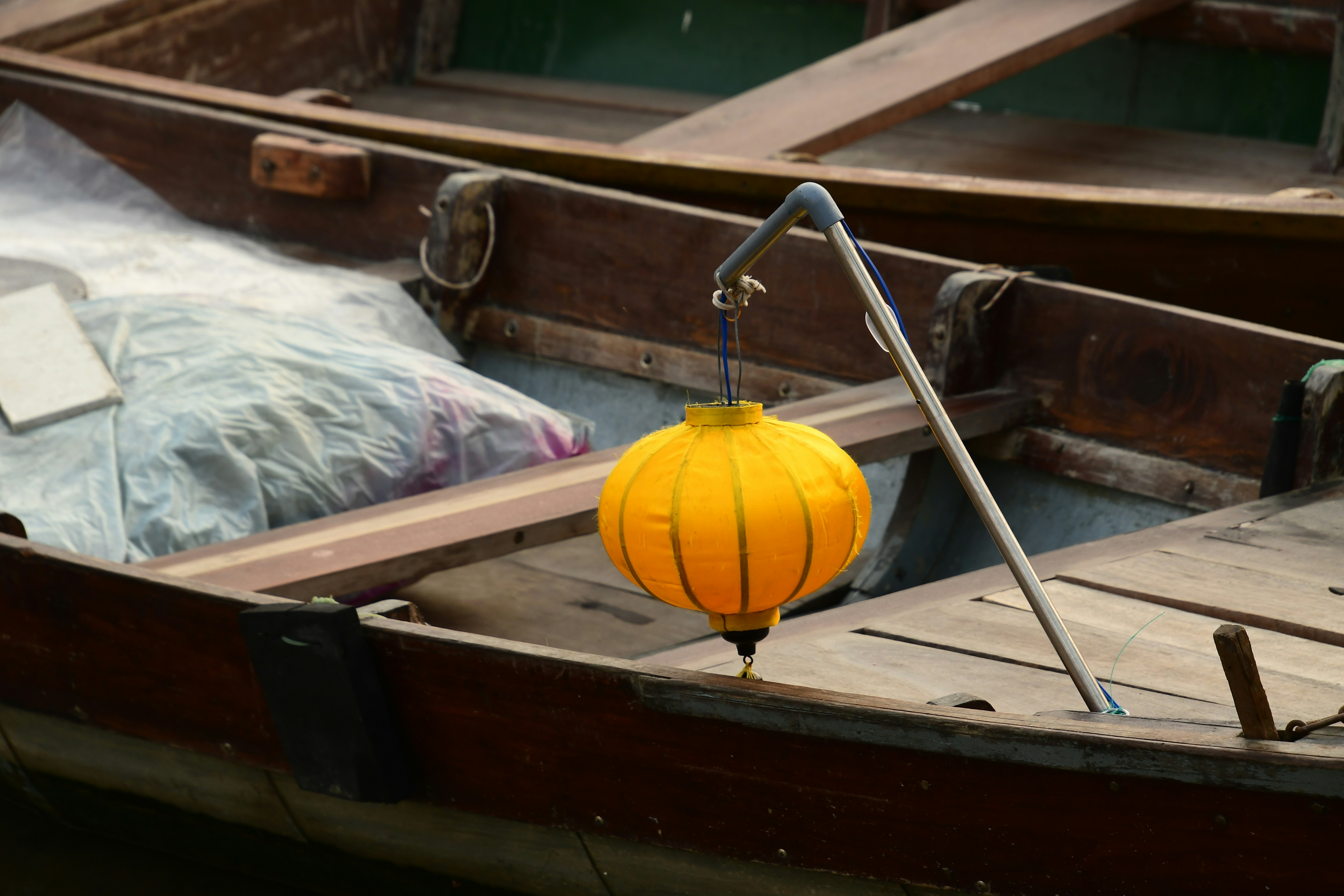Amber Lantern Dangling Above Weathered Boats in a Quiet Marina