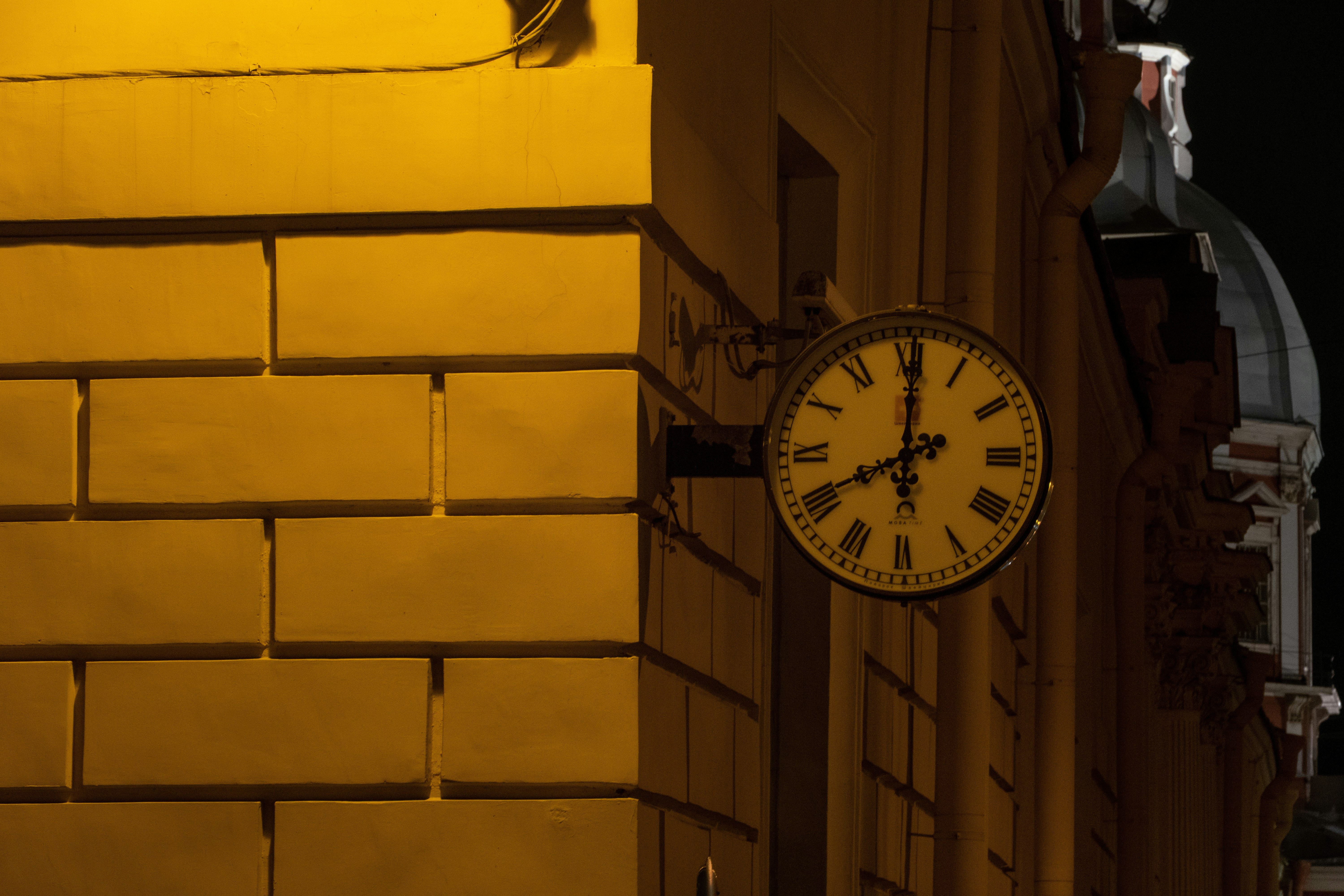 Amber Hour: A Vintage Street Clock Clinging to a Stone Facade